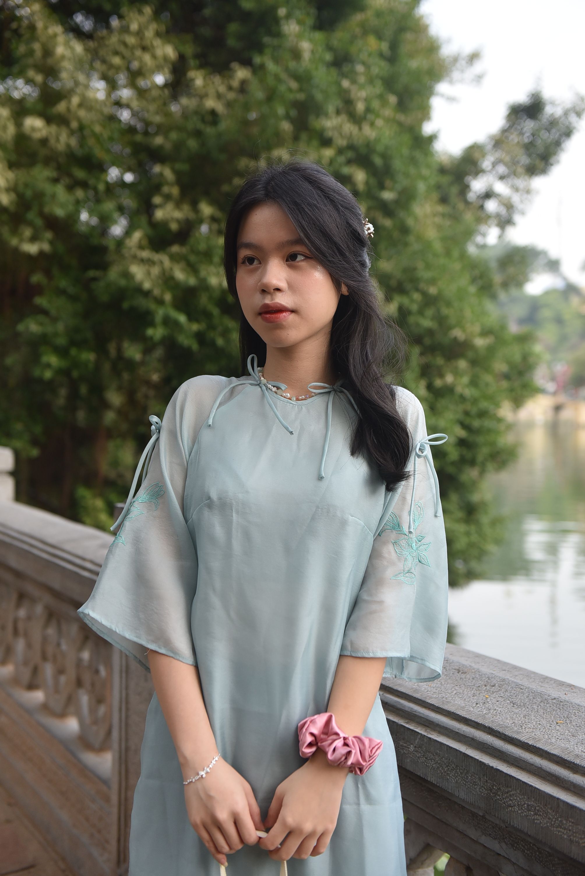 Woman Wearing Loose Dress and Pink Scrunchie Standing on Stone Bridge ...