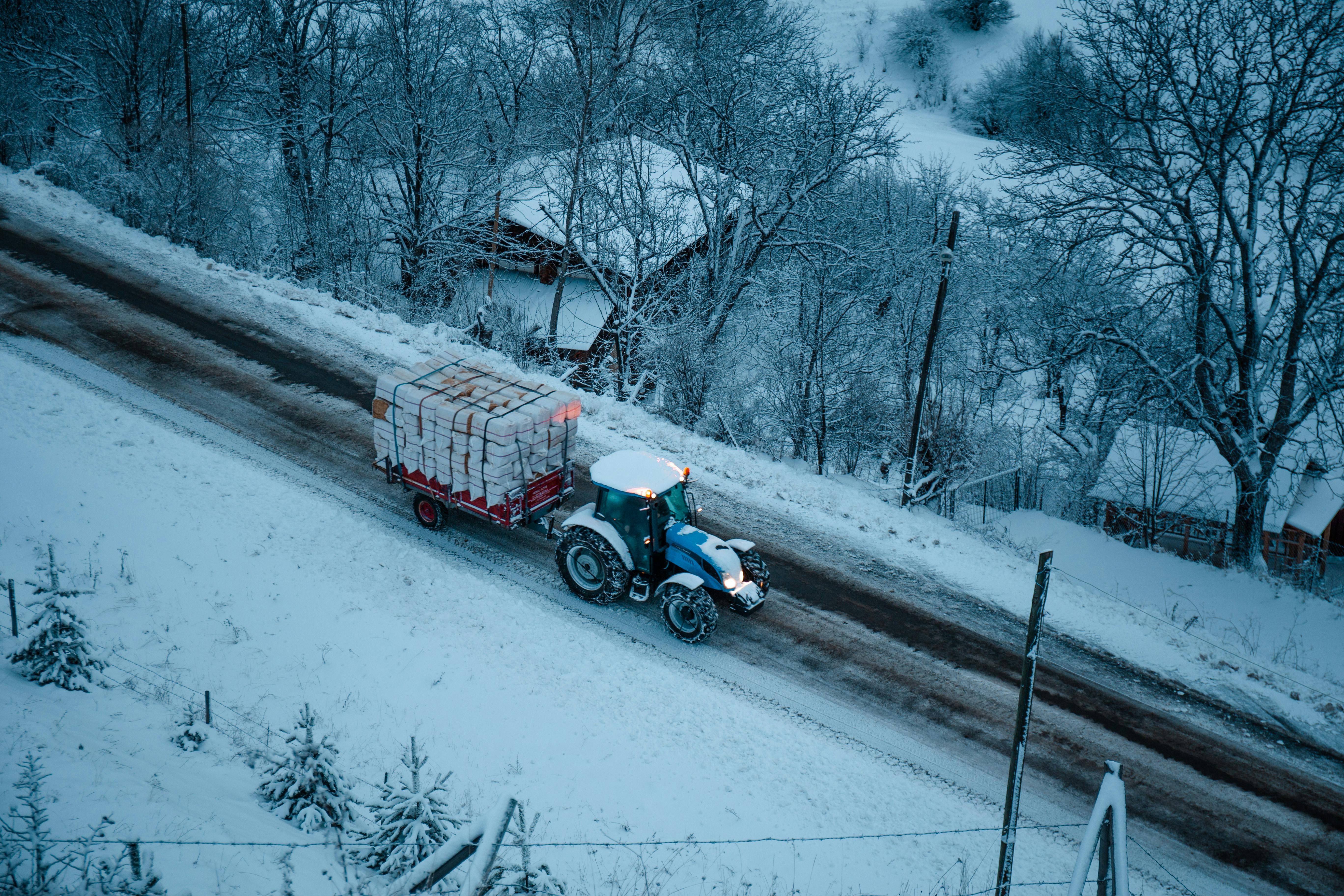 A Tractor with a Trailer Driving on a Snowy Road · Free Stock Photo