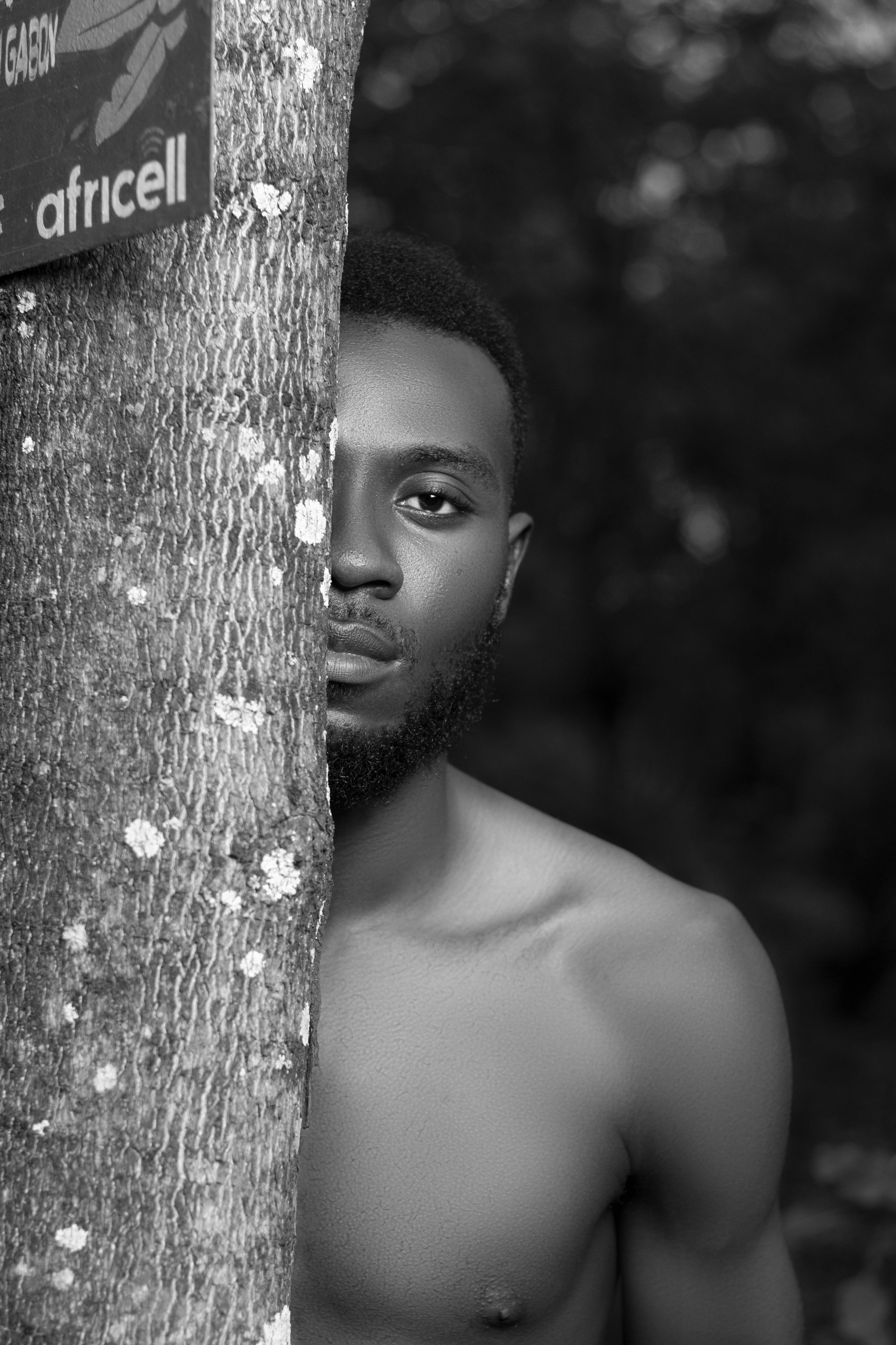 Shirtless Man Standing behind a Tree · Free Stock Photo
