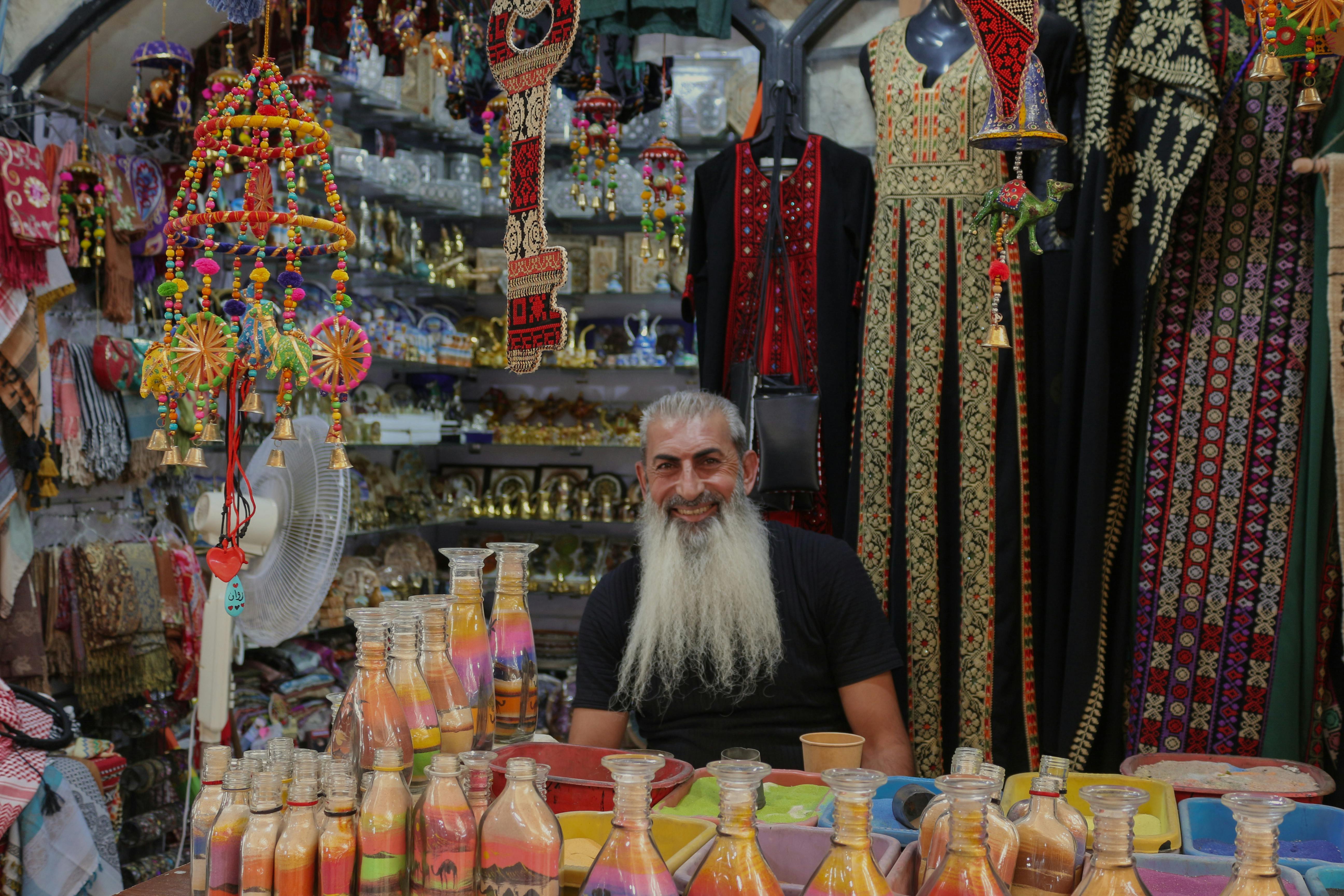 Smiling Merchant in Stall with Souvenirs · Free Stock Photo