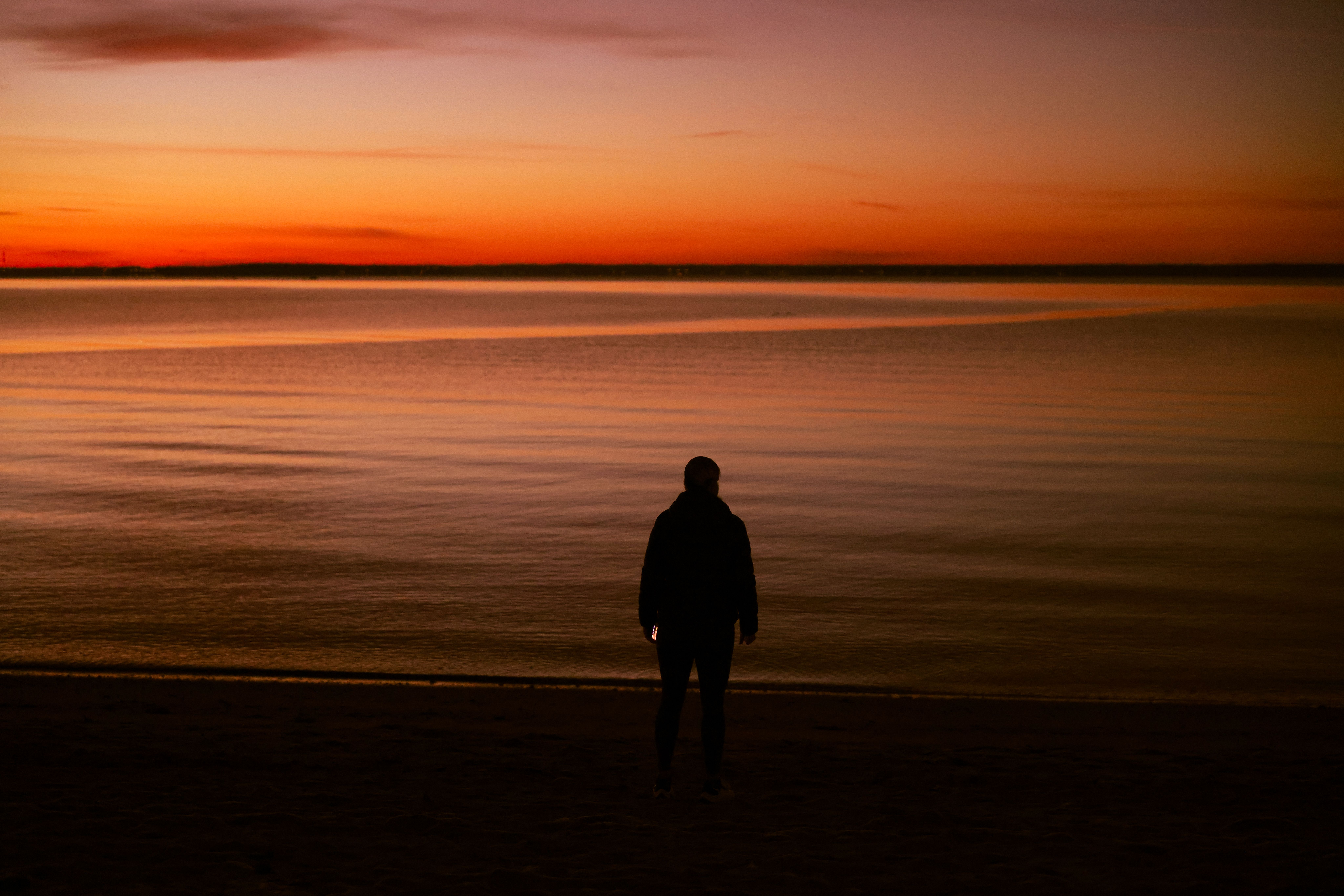 Silhouette of a Person Standing Alone on a Coast at Dusk · Free Stock Photo