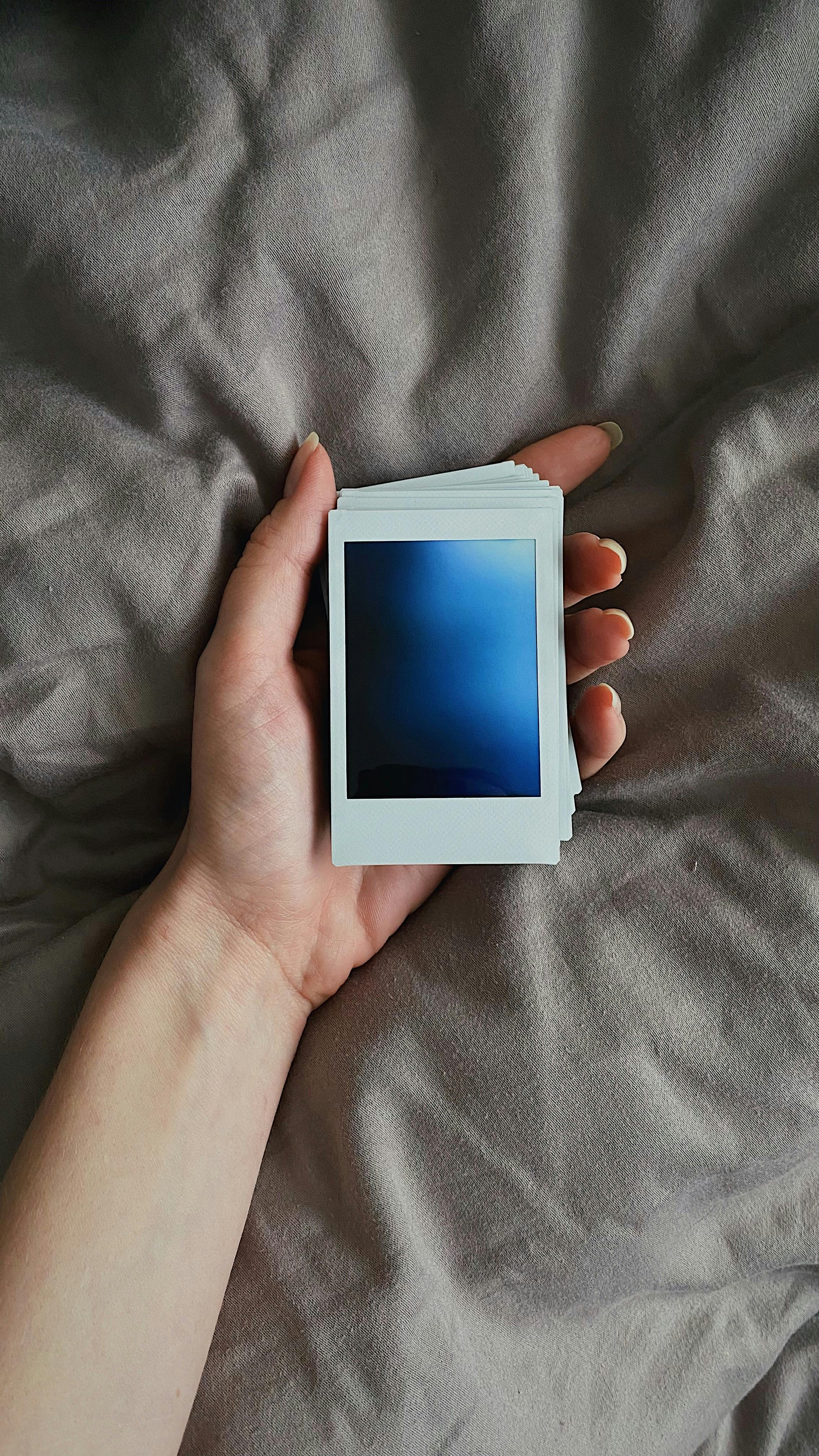 Person Holding a Stack of Polaroid Pictures · Free Stock Photo