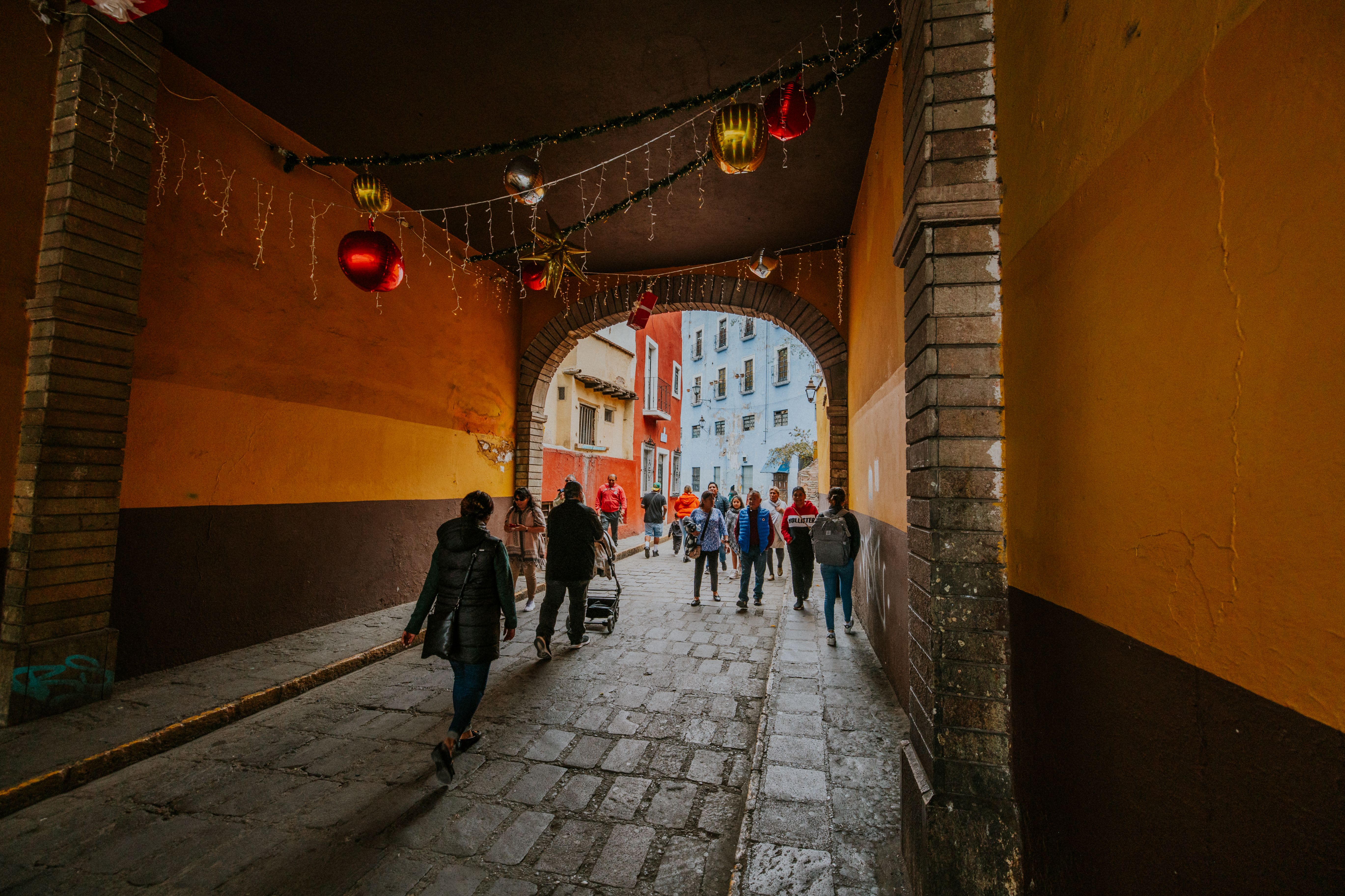People walking through an alleyway with yellow and orange lights · Free ...