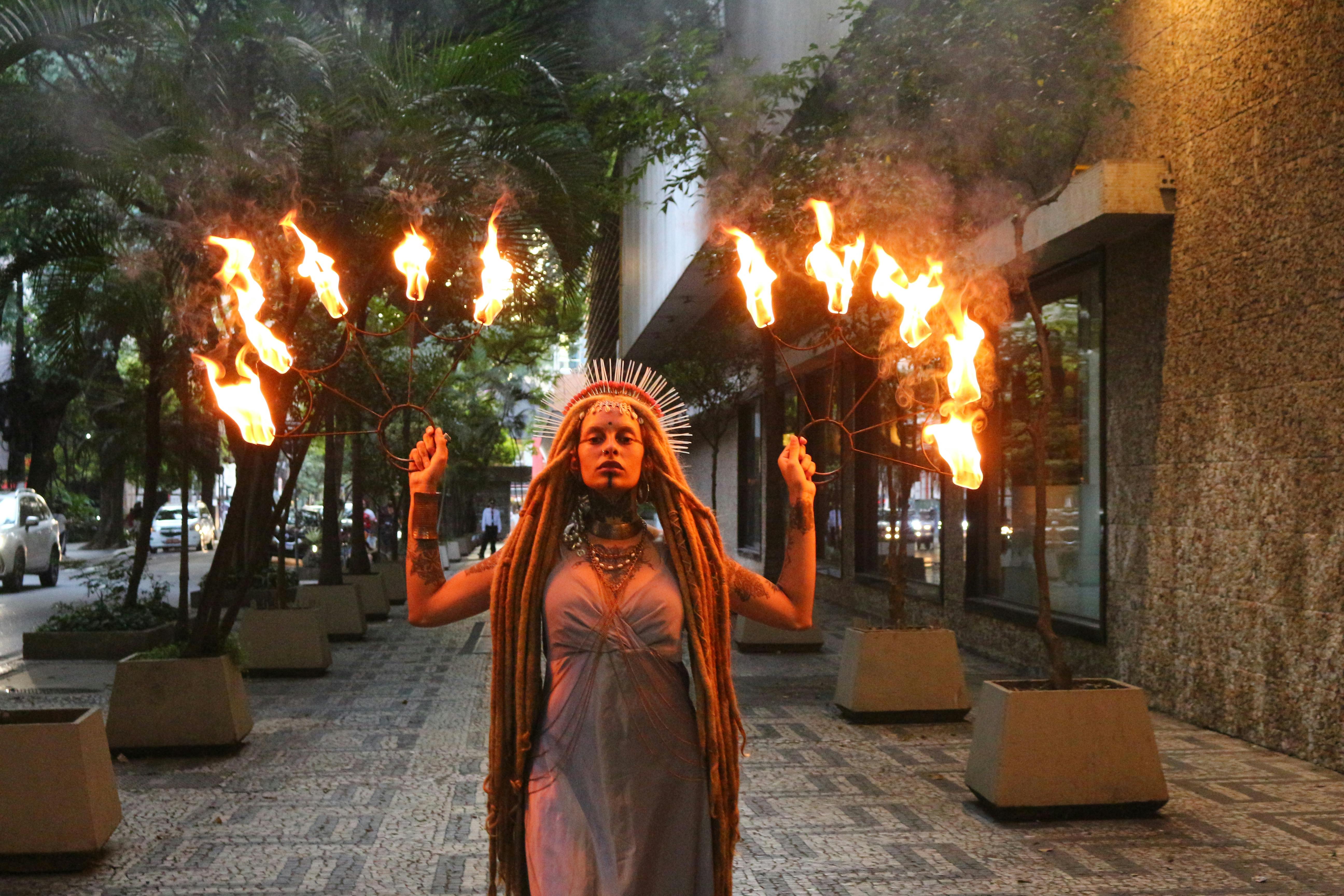 Fire Performer with Long Dreadlocks Standing on Sidewalk · Free Stock Photo