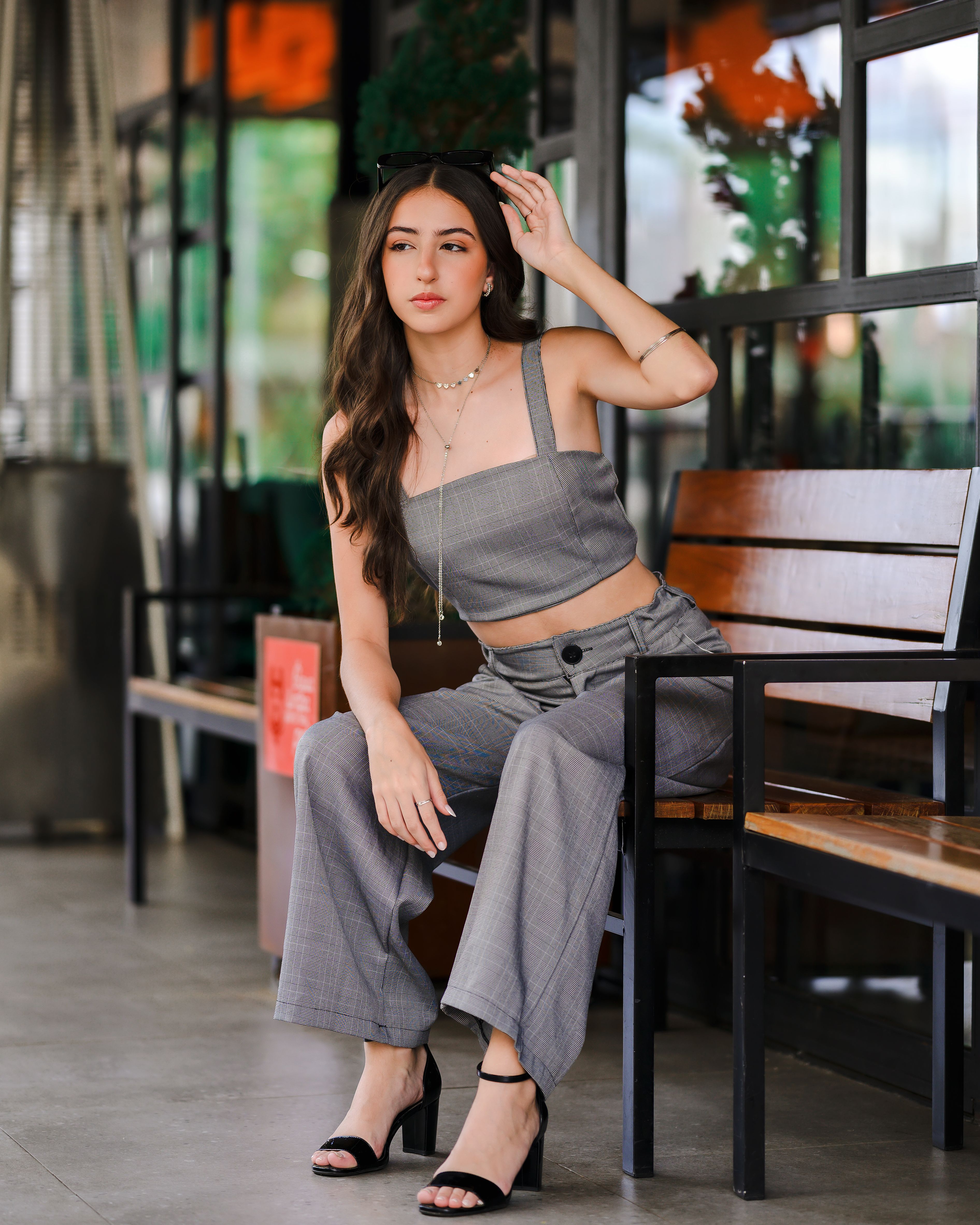 Woman Sitting with Hand Raised on Bench · Free Stock Photo