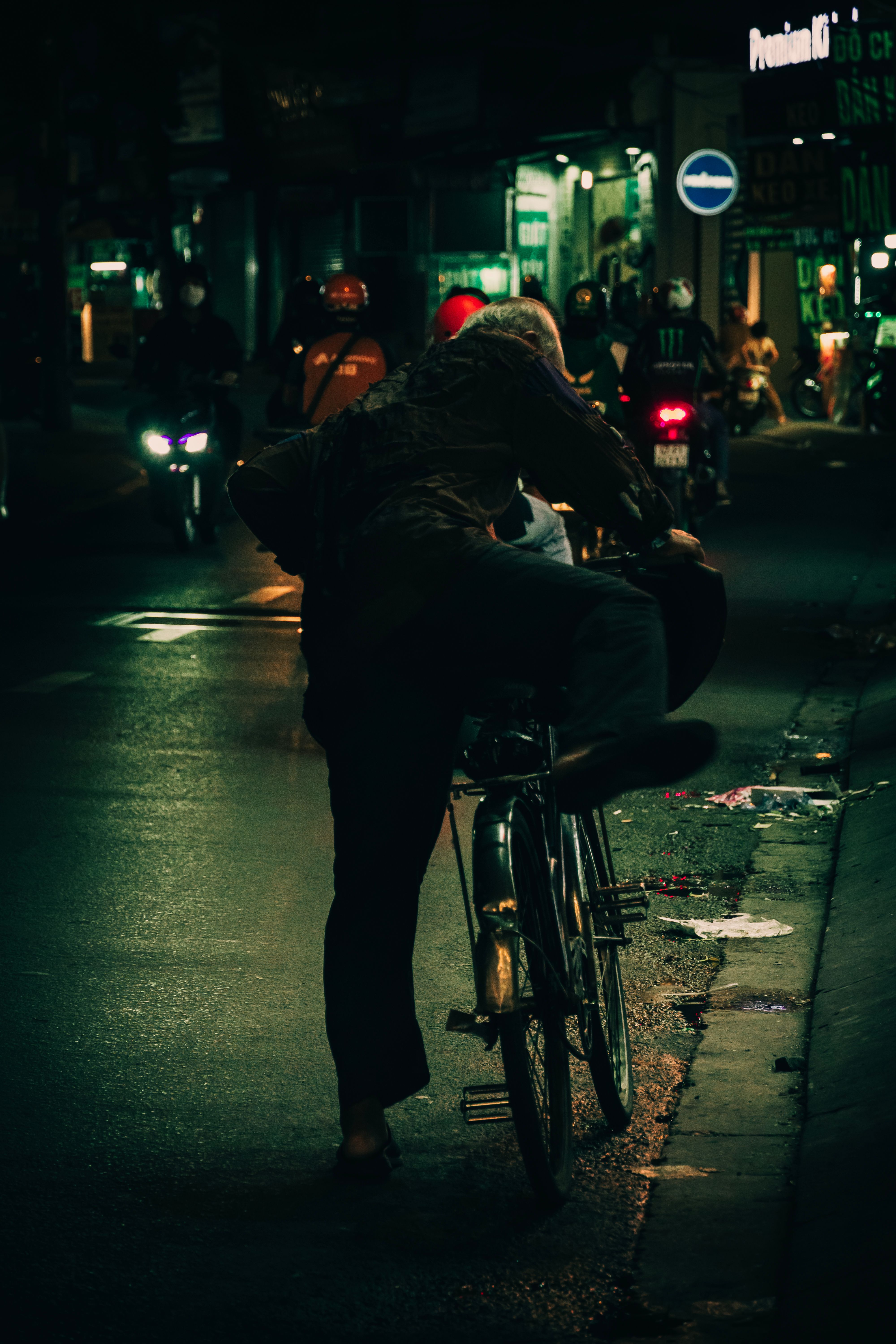 Back View of a Man Getting on a Bicycle on the Street in City at Night ...
