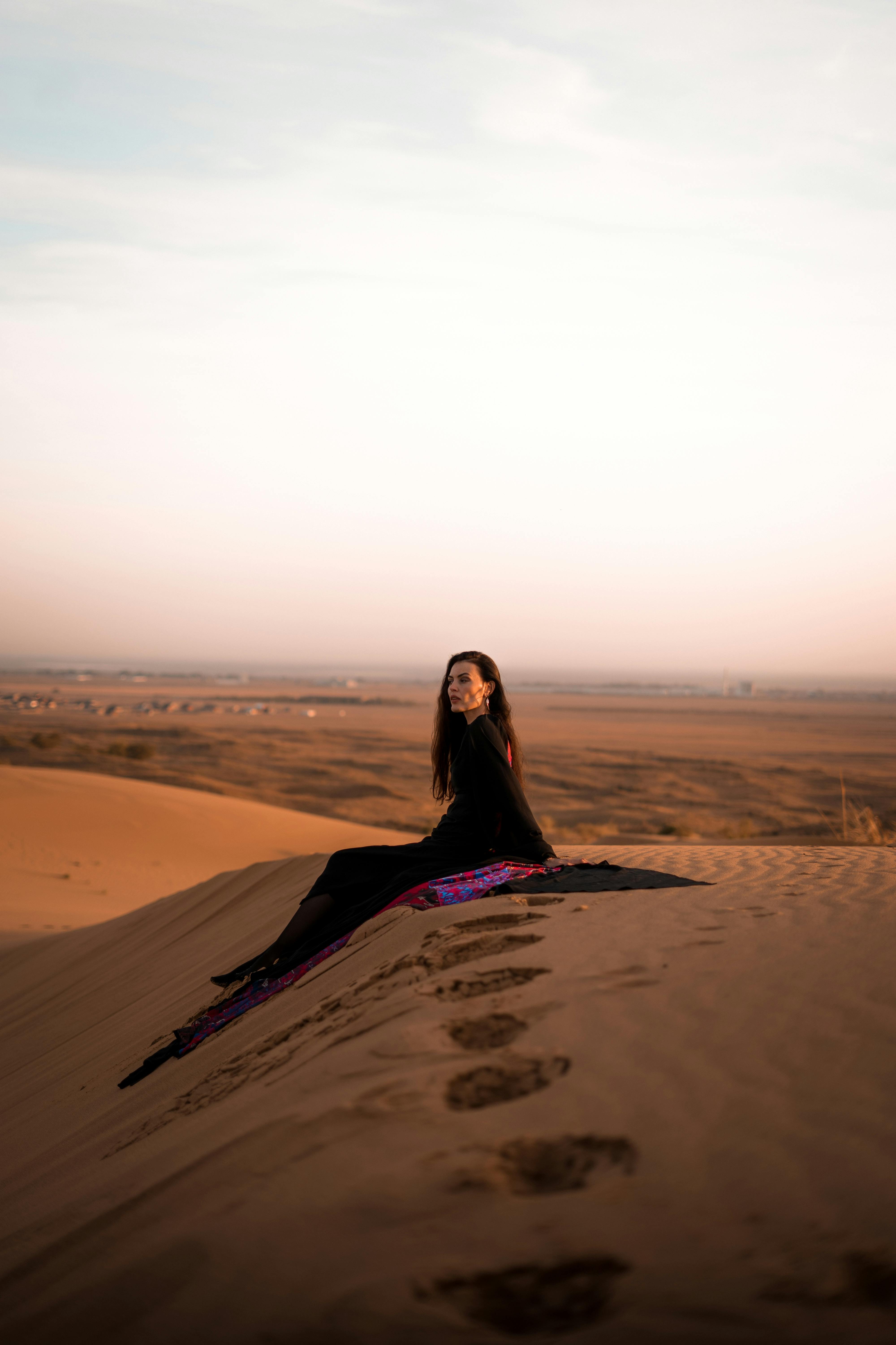 Woman Sitting on Dune on Desert · Free Stock Photo