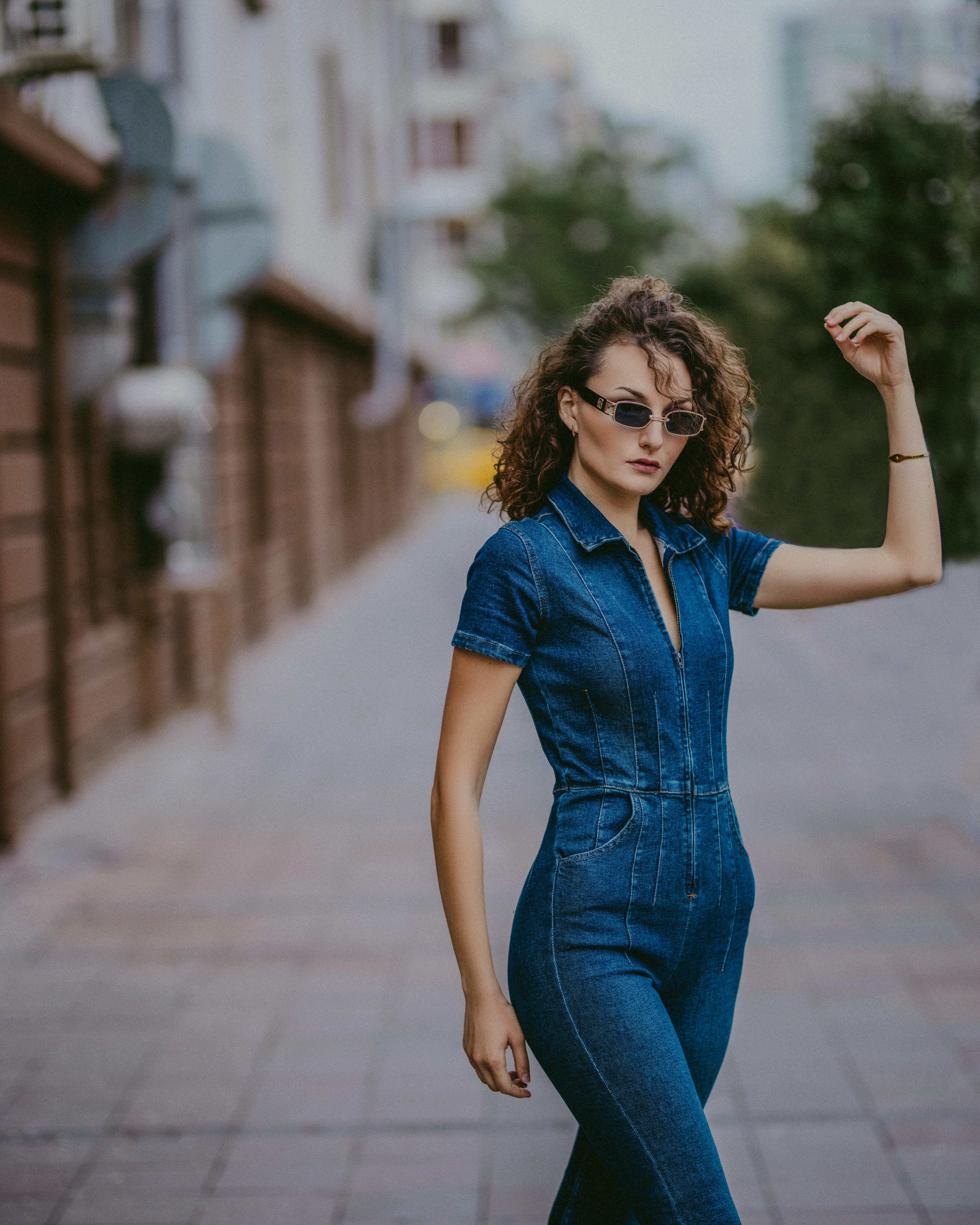 Woman in Denim Overalls and Sunglasses Walking Sidewalk · Free Stock Photo