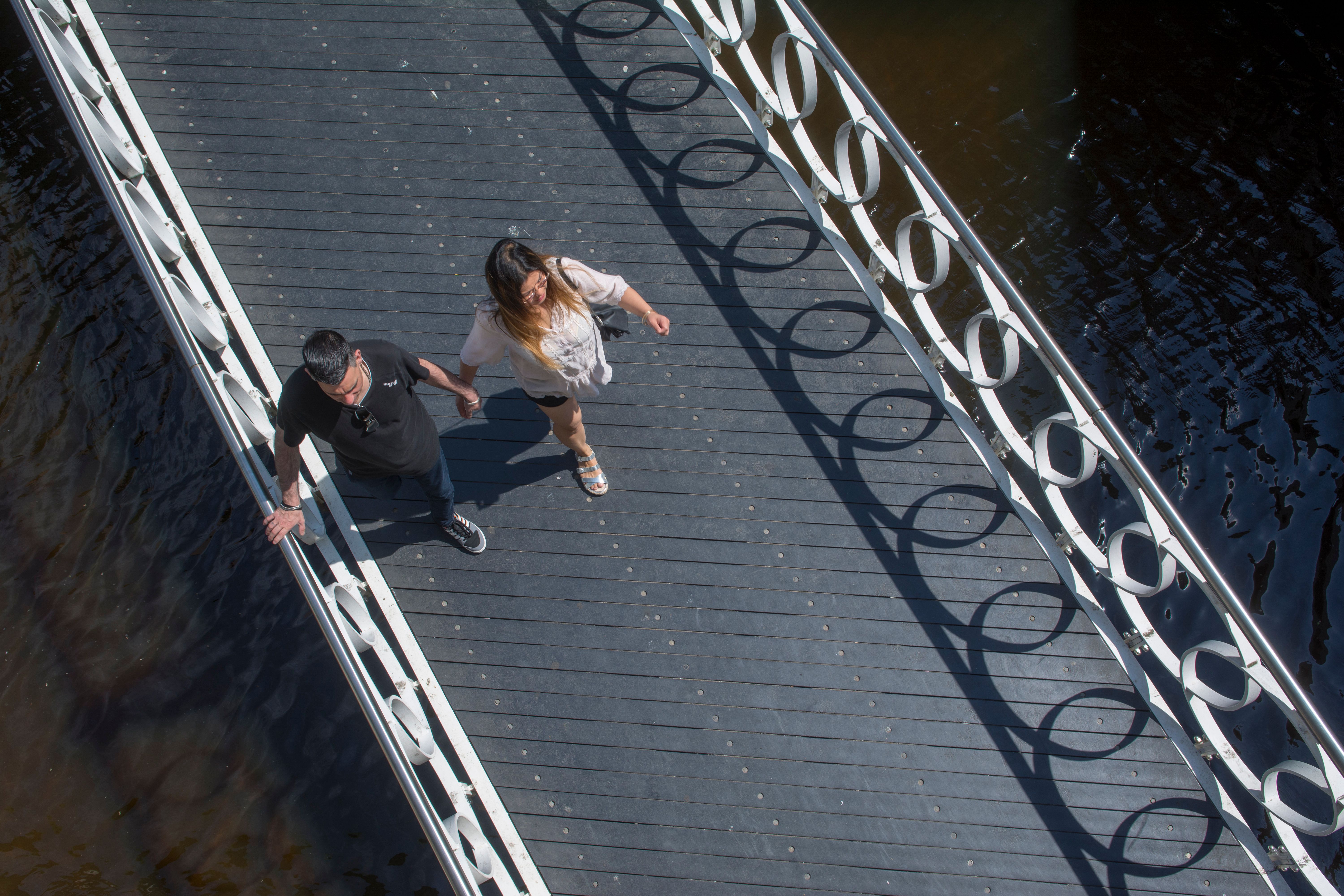 Couple Holding Hands While Walking on Bridge · Free Stock Photo