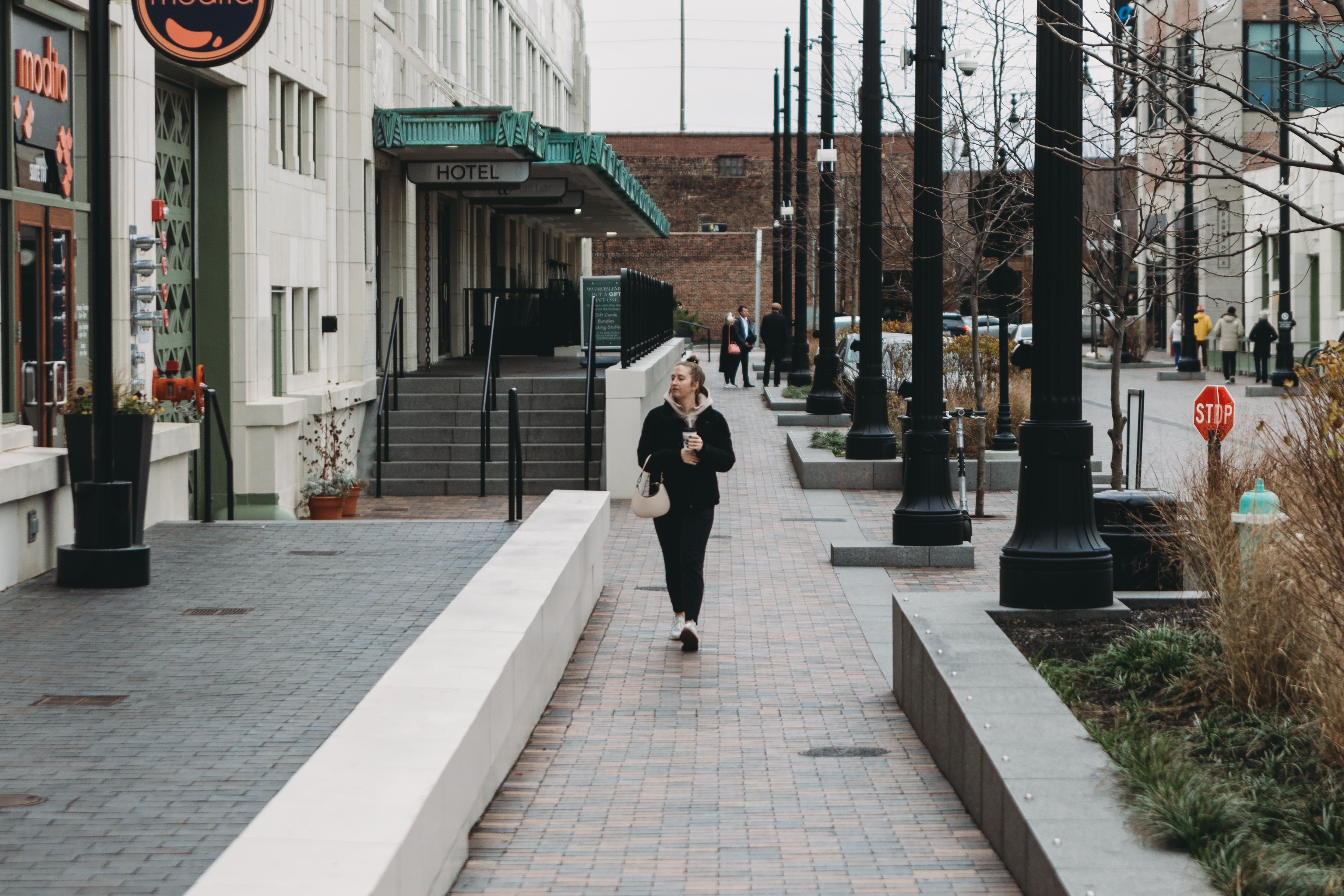 Passerby with a Cup of Coffee Walking Along the Sidewalk · Free Stock Photo