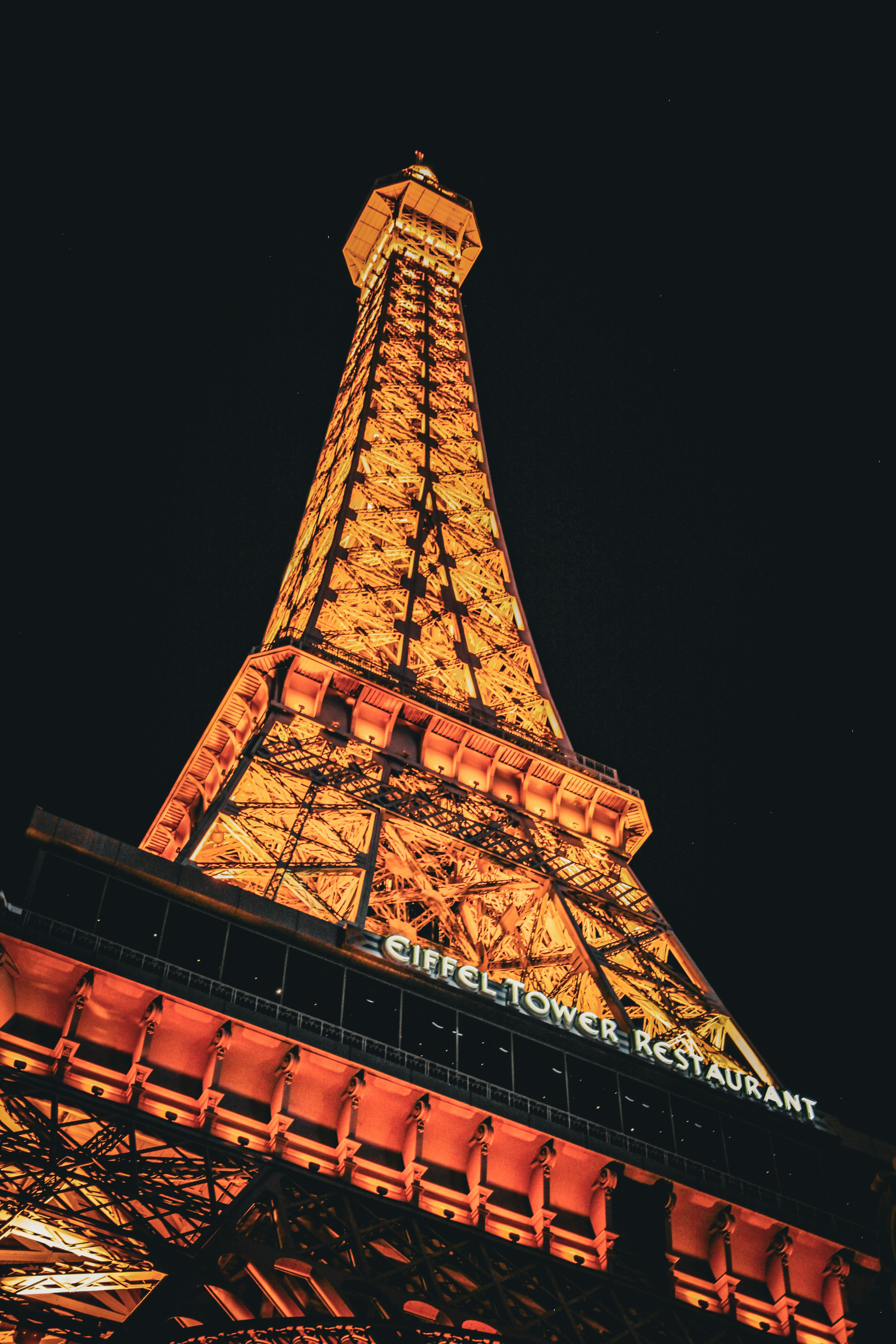 The eiffel tower is lit up in orange at night · Free Stock Photo
