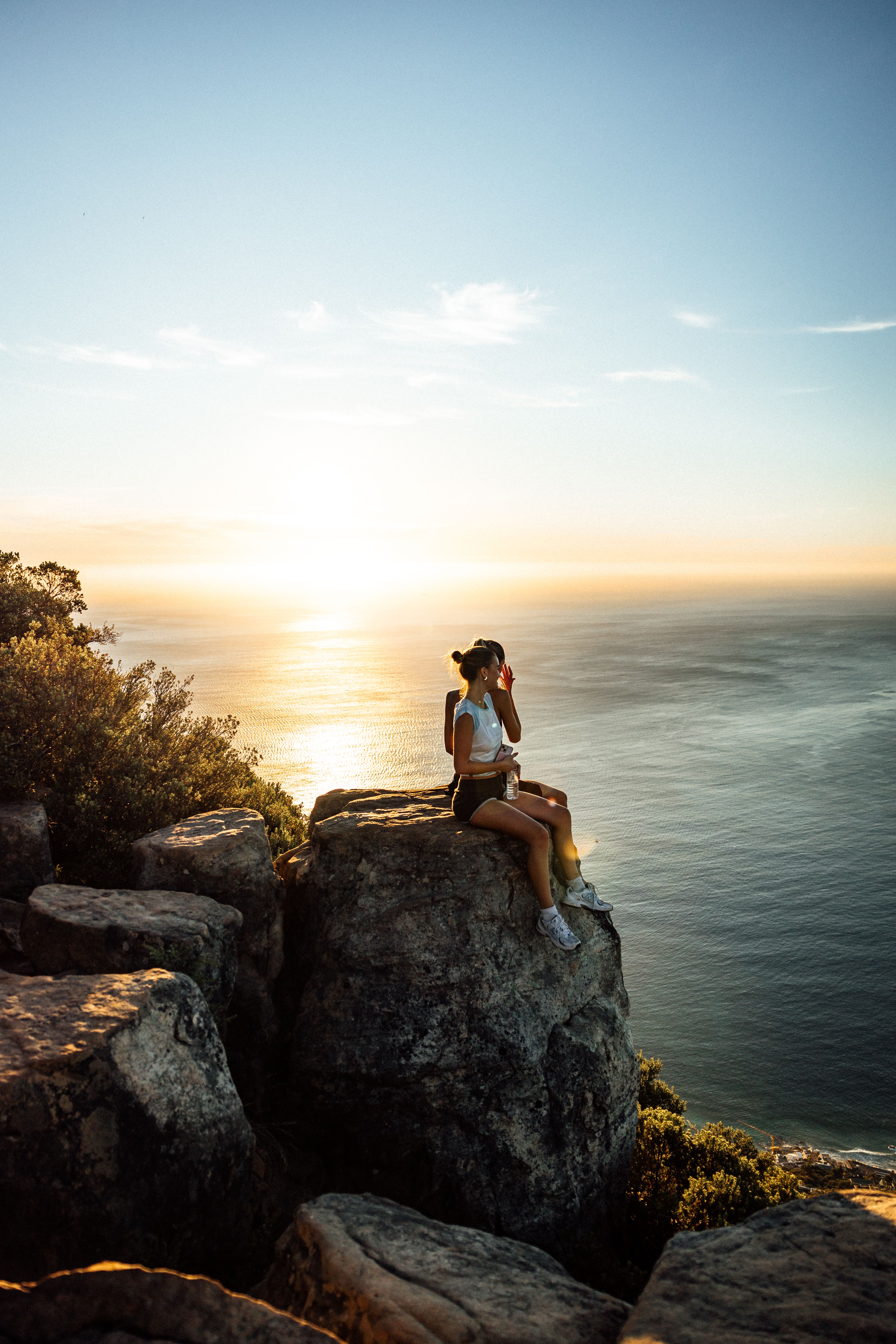 Sitting on a Rock Overhang of a Seaside Cliff at Sunset · Free Stock Photo