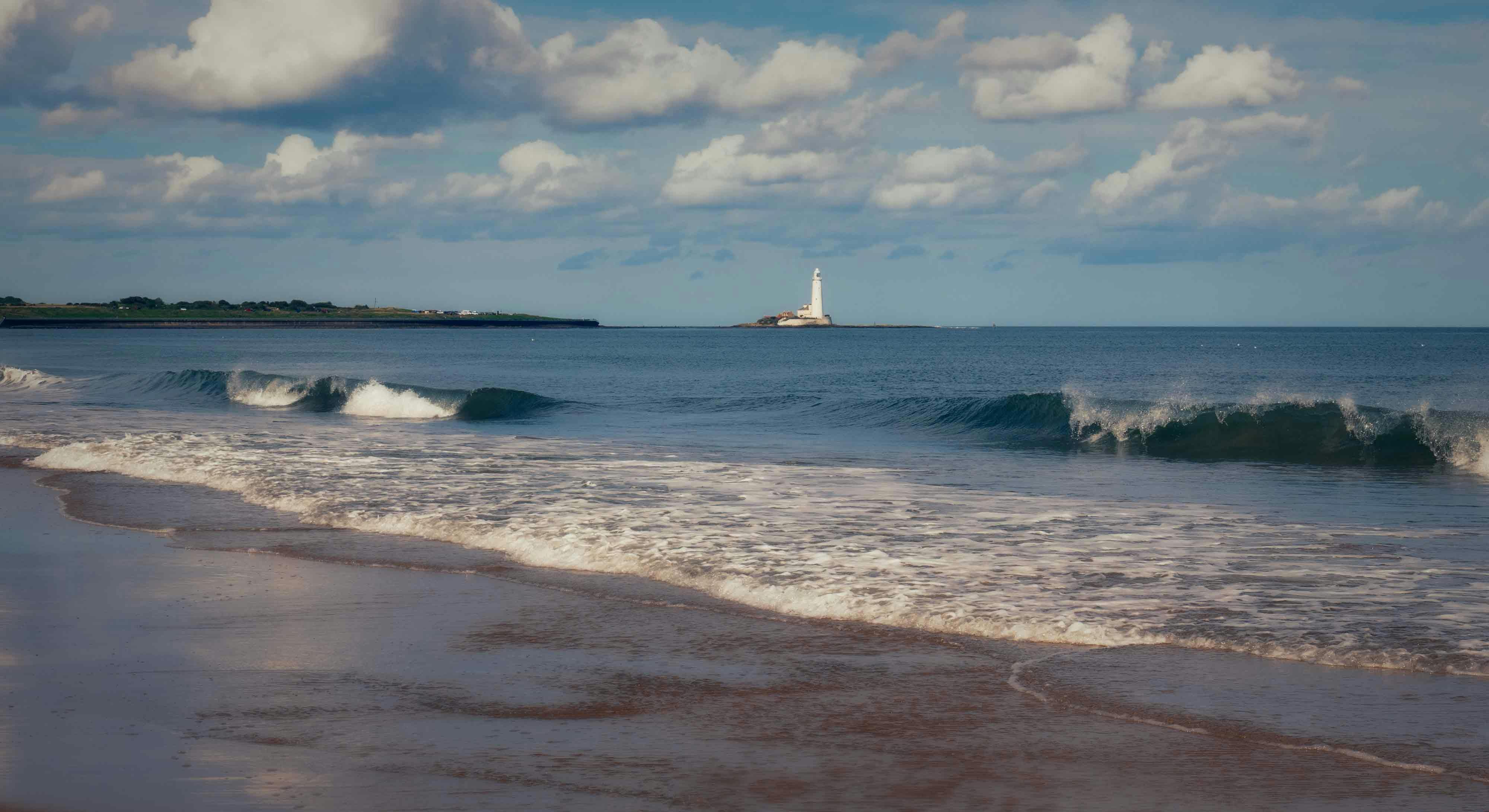 Waves Crashing onto Sea Shore with Lighthouse in Backg · Free Stock Photo