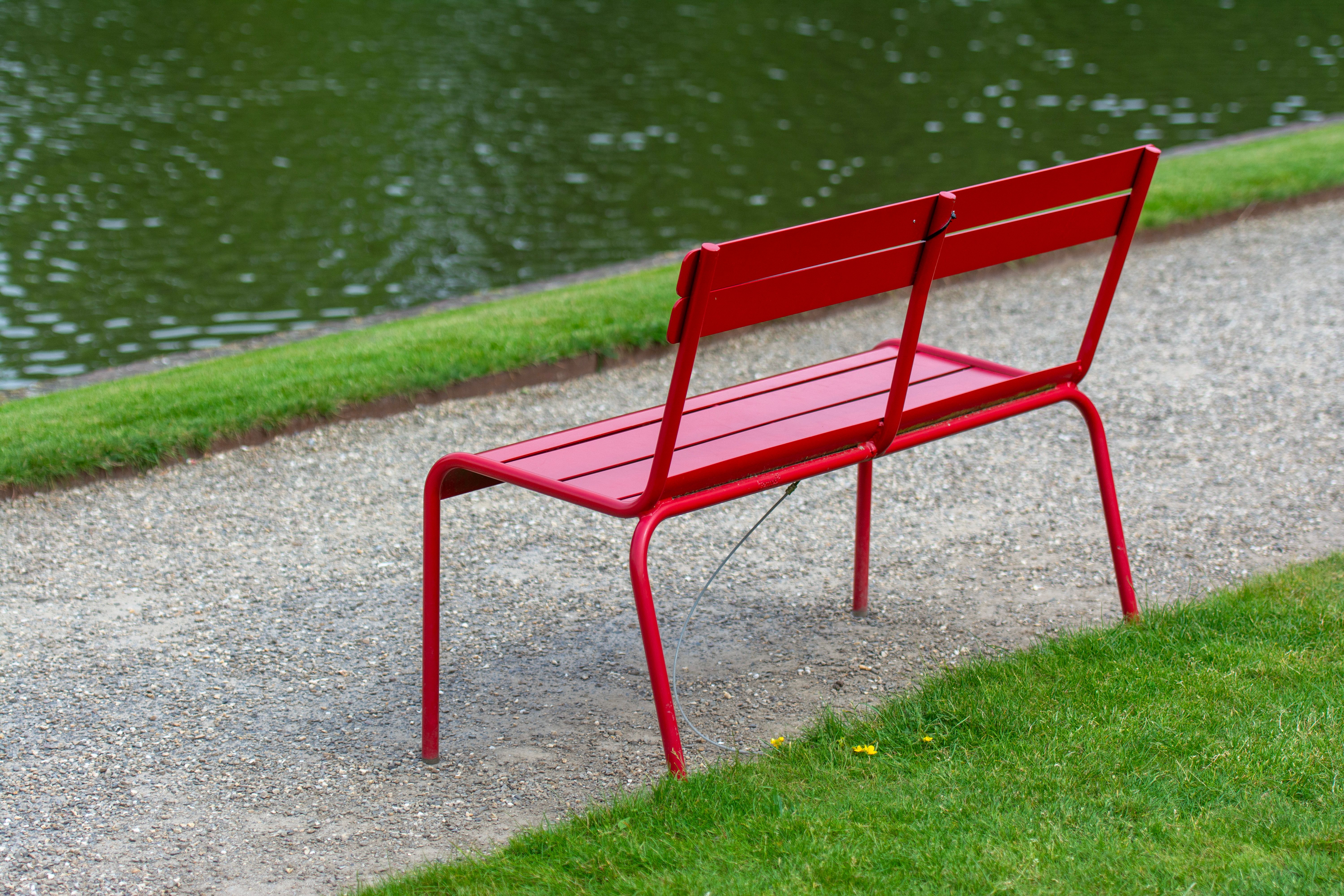 An Empty Red Bench by a Body of Water in a Park · Free Stock Photo
