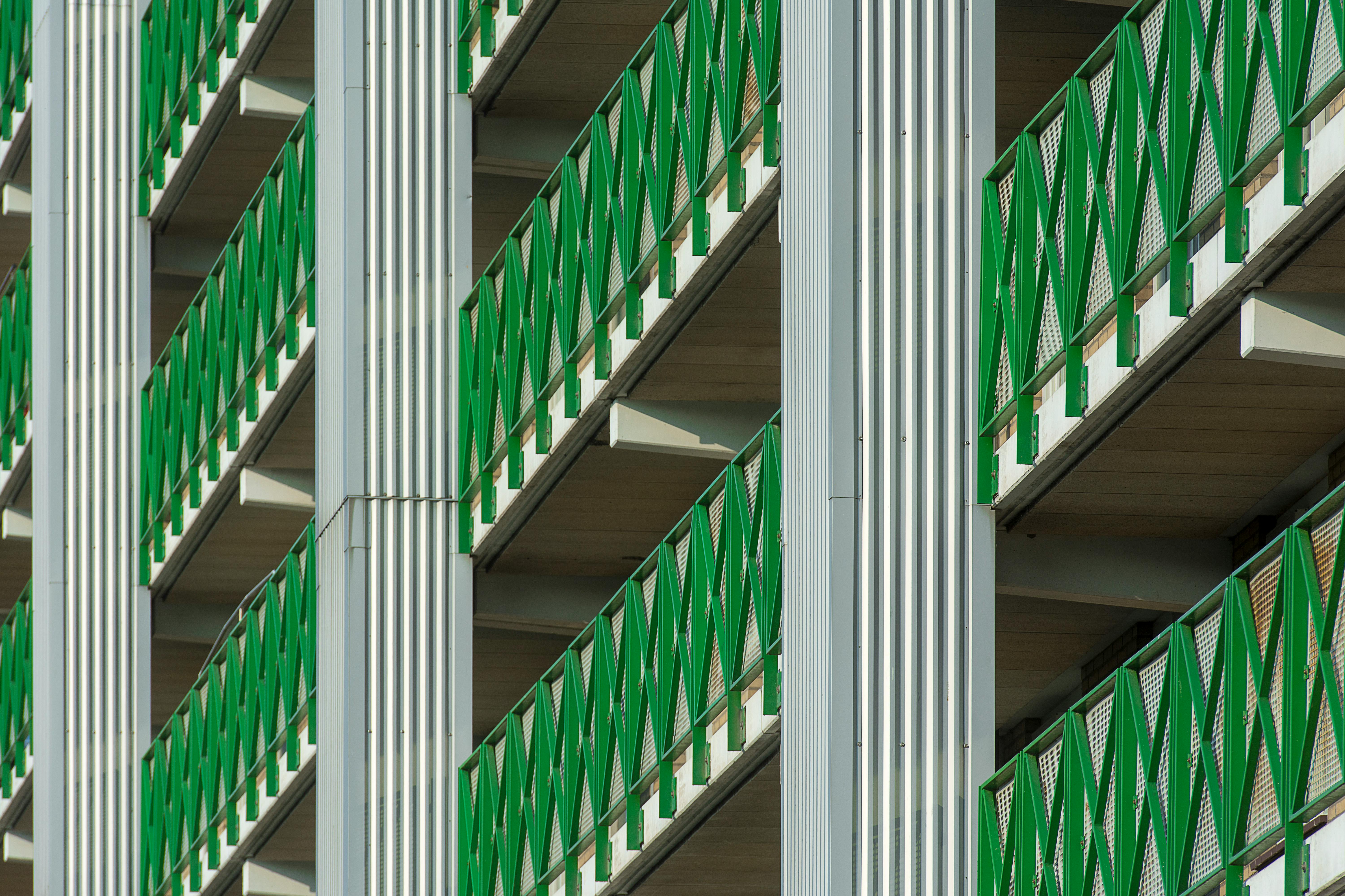 A green and white building with balconies and green railing · Free ...