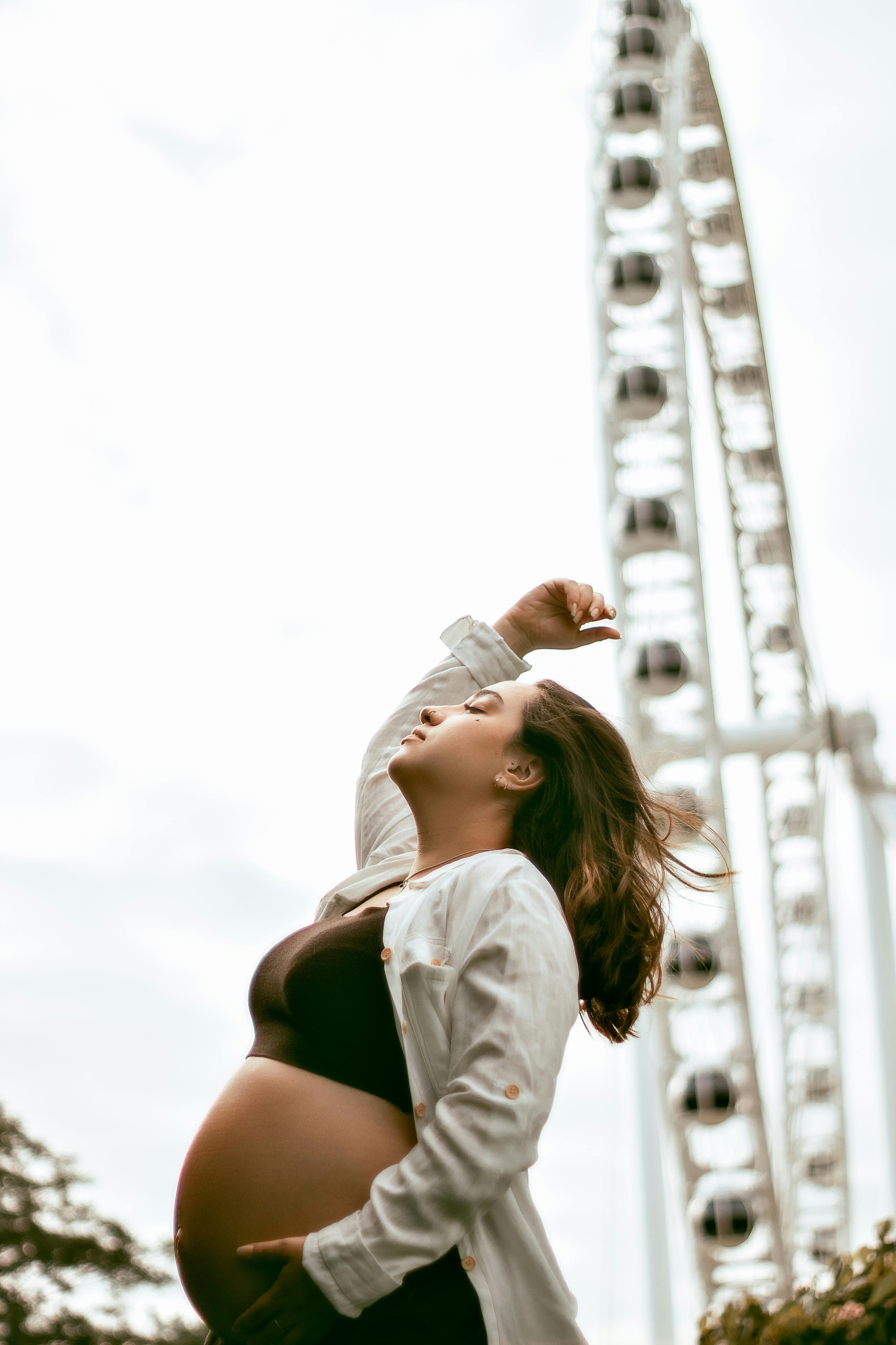 Pregnant Woman in Front of Ferris Wheel · Free Stock Photo