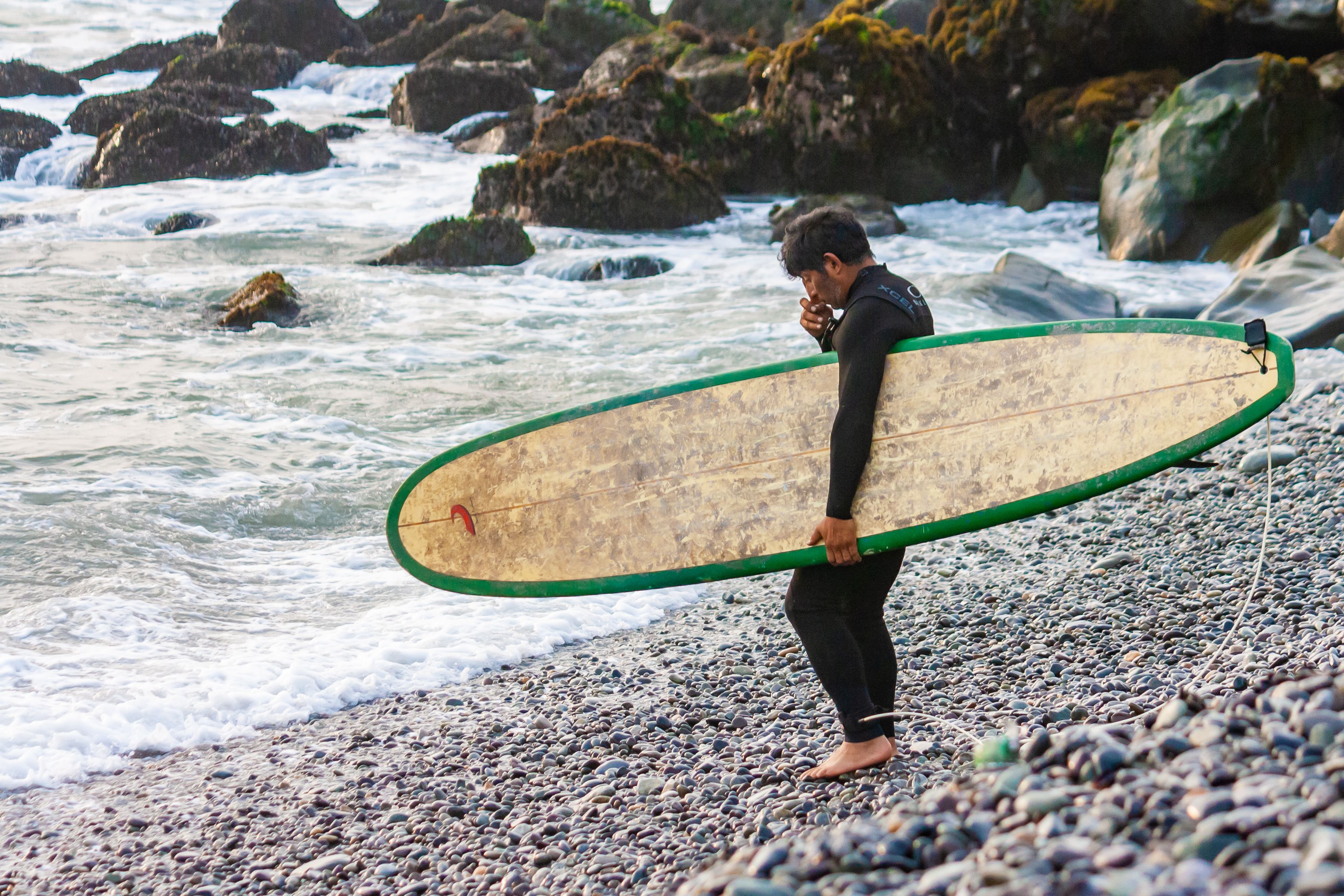 Surfer with a Board Under His Arm Standing on the Pebbles of the Beach ...