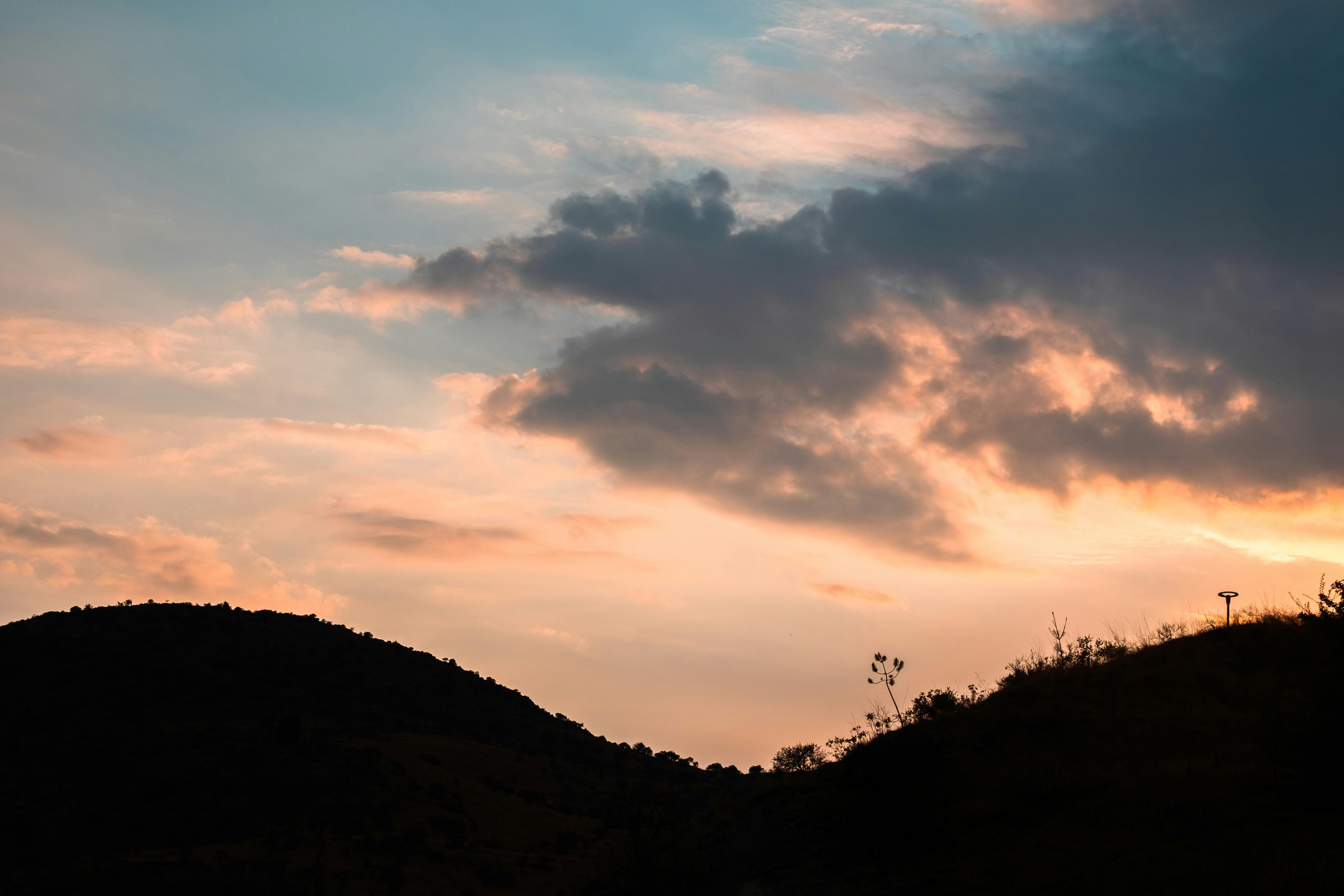 A sunset over a hill with clouds and trees · Free Stock Photo