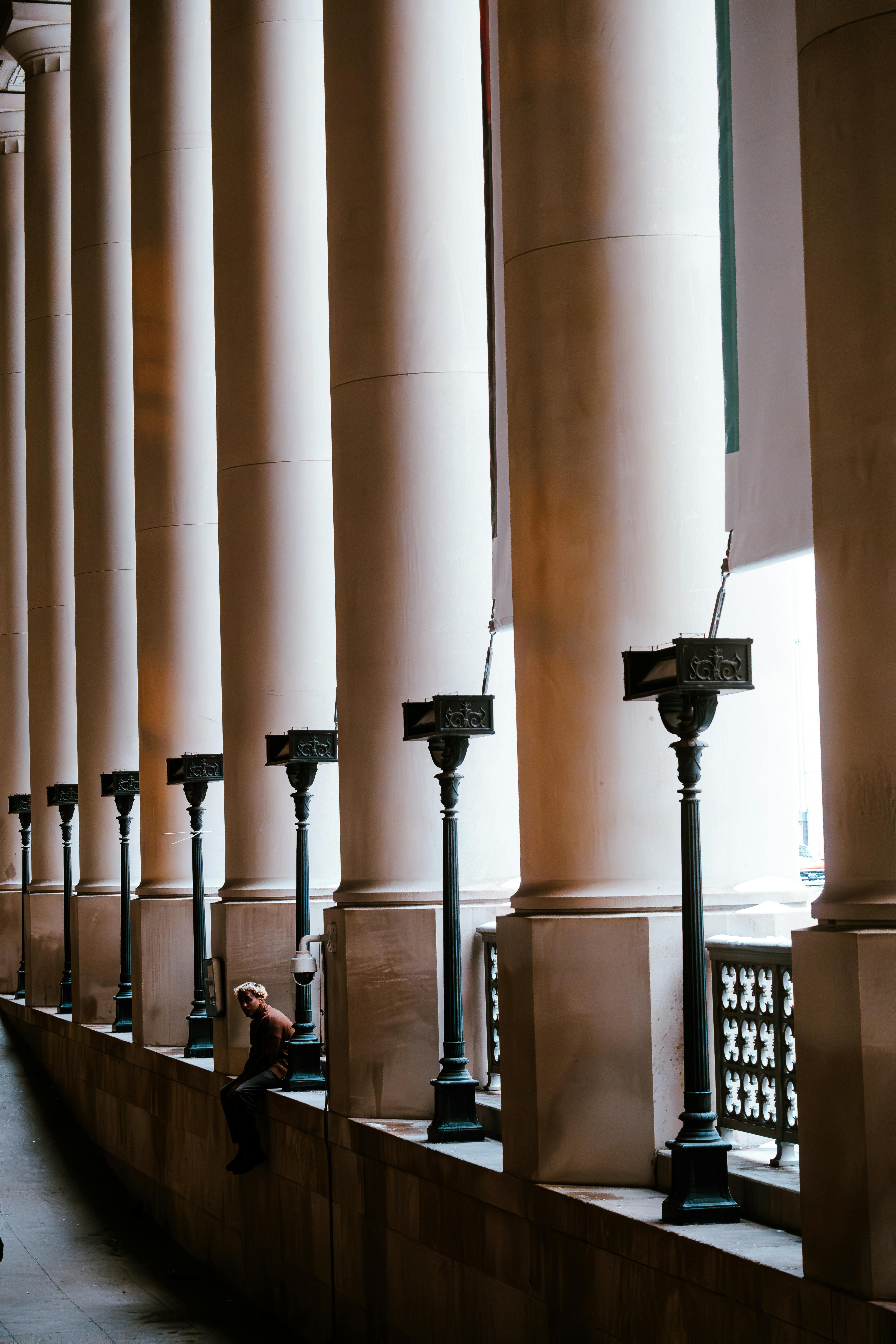 Person Sitting by Monumental Colonnade · Free Stock Photo