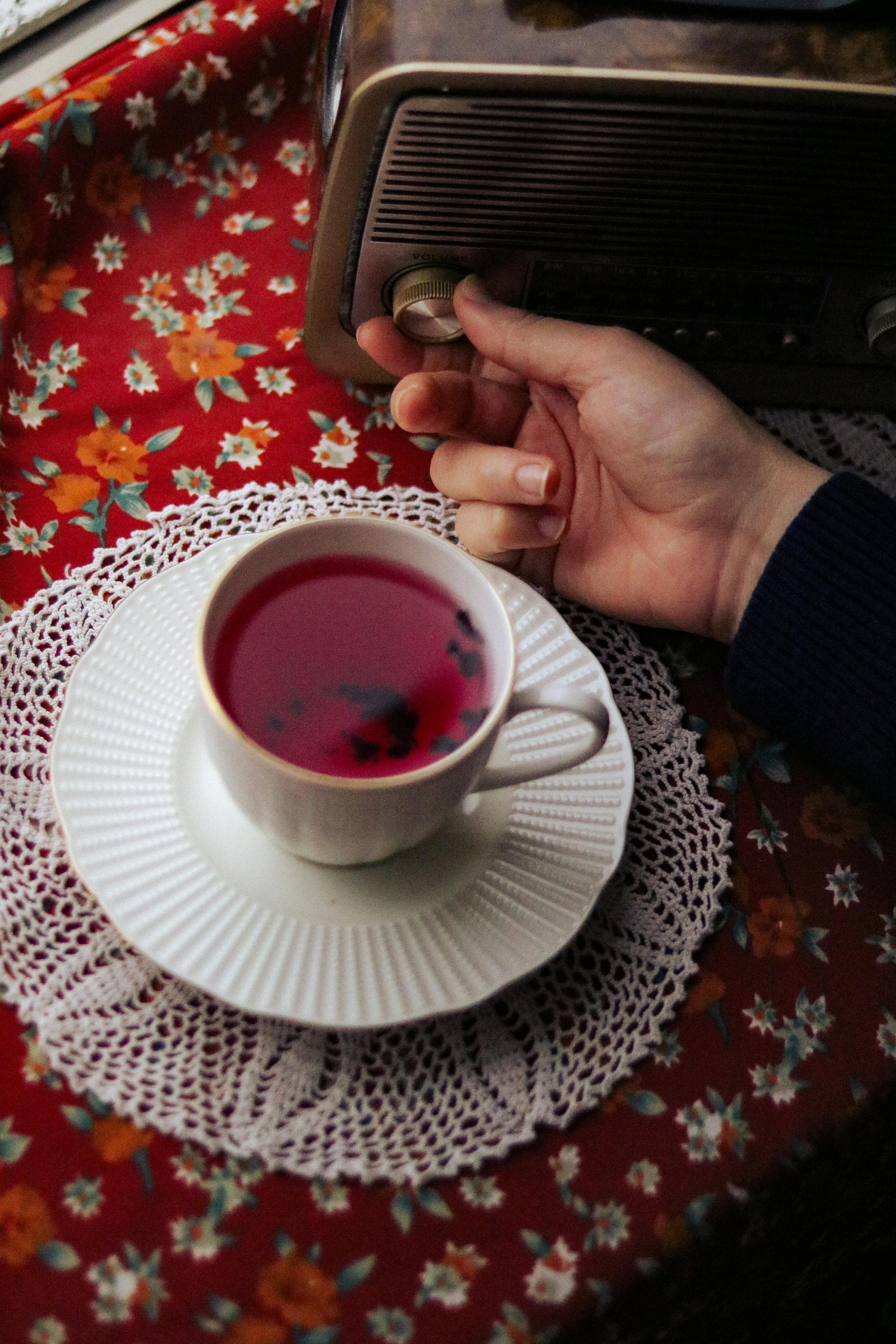 Person Tuning a Vintage Radio next to a Tea Cup · Free Stock Photo