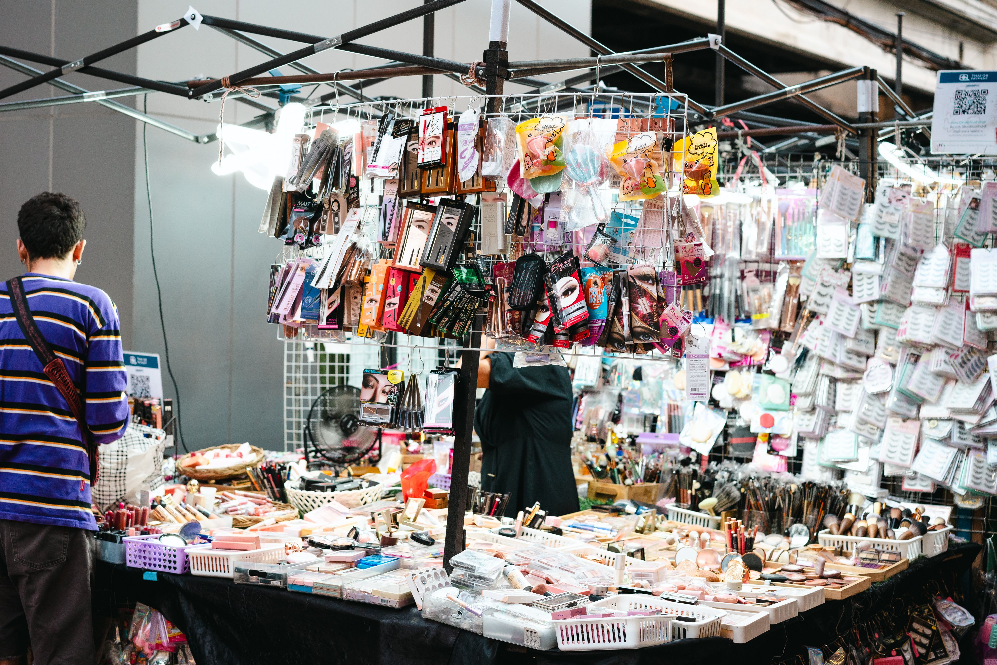A woman is looking at a stall with many items · Free Stock Photo