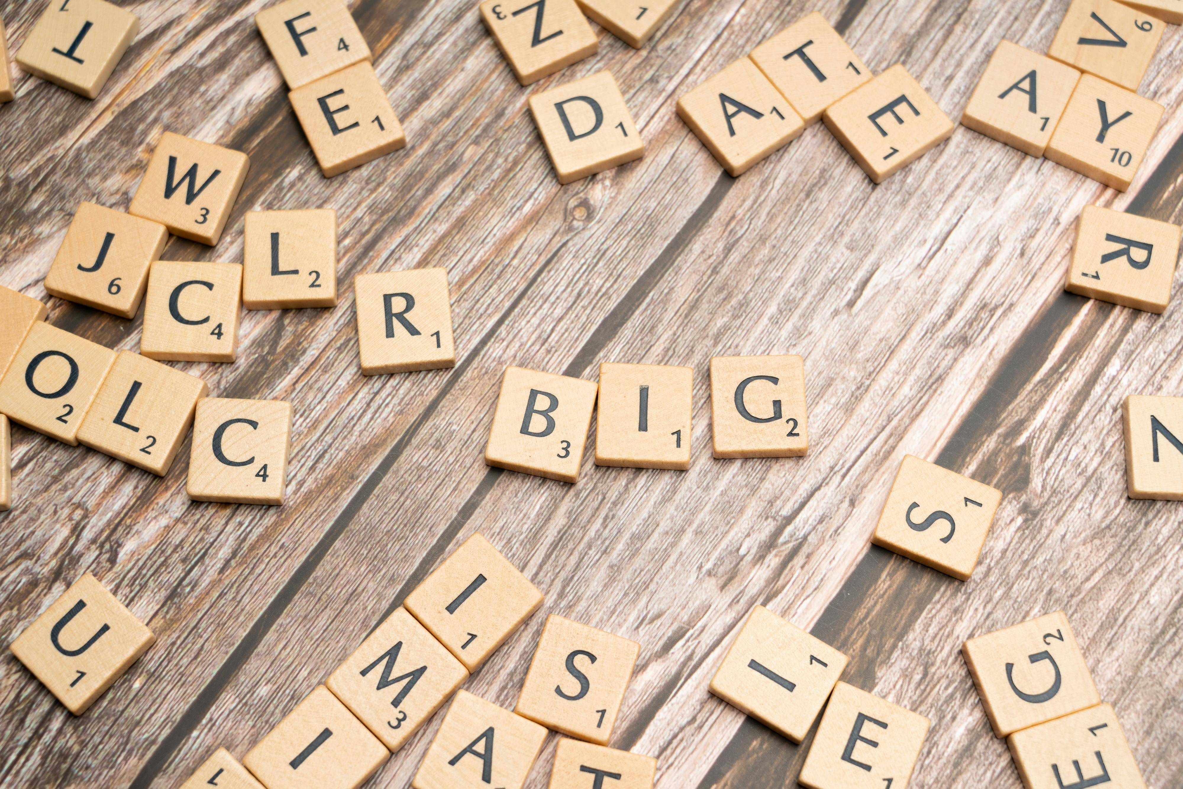 Scrabble letters spelling big on a wooden table · Free Stock Photo