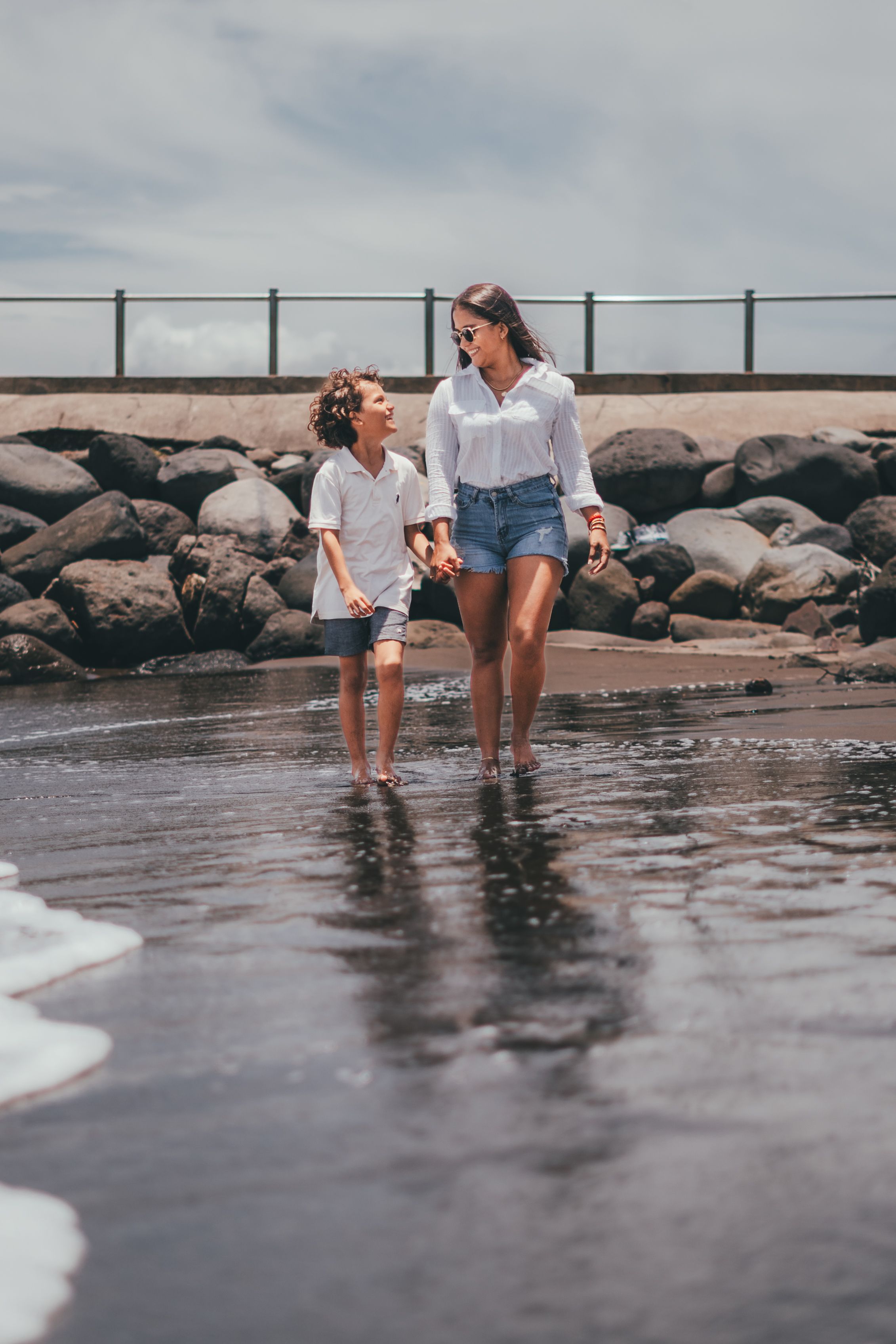 Woman with Her Son Walking Ankles Deep in Water and Smiling · Free ...