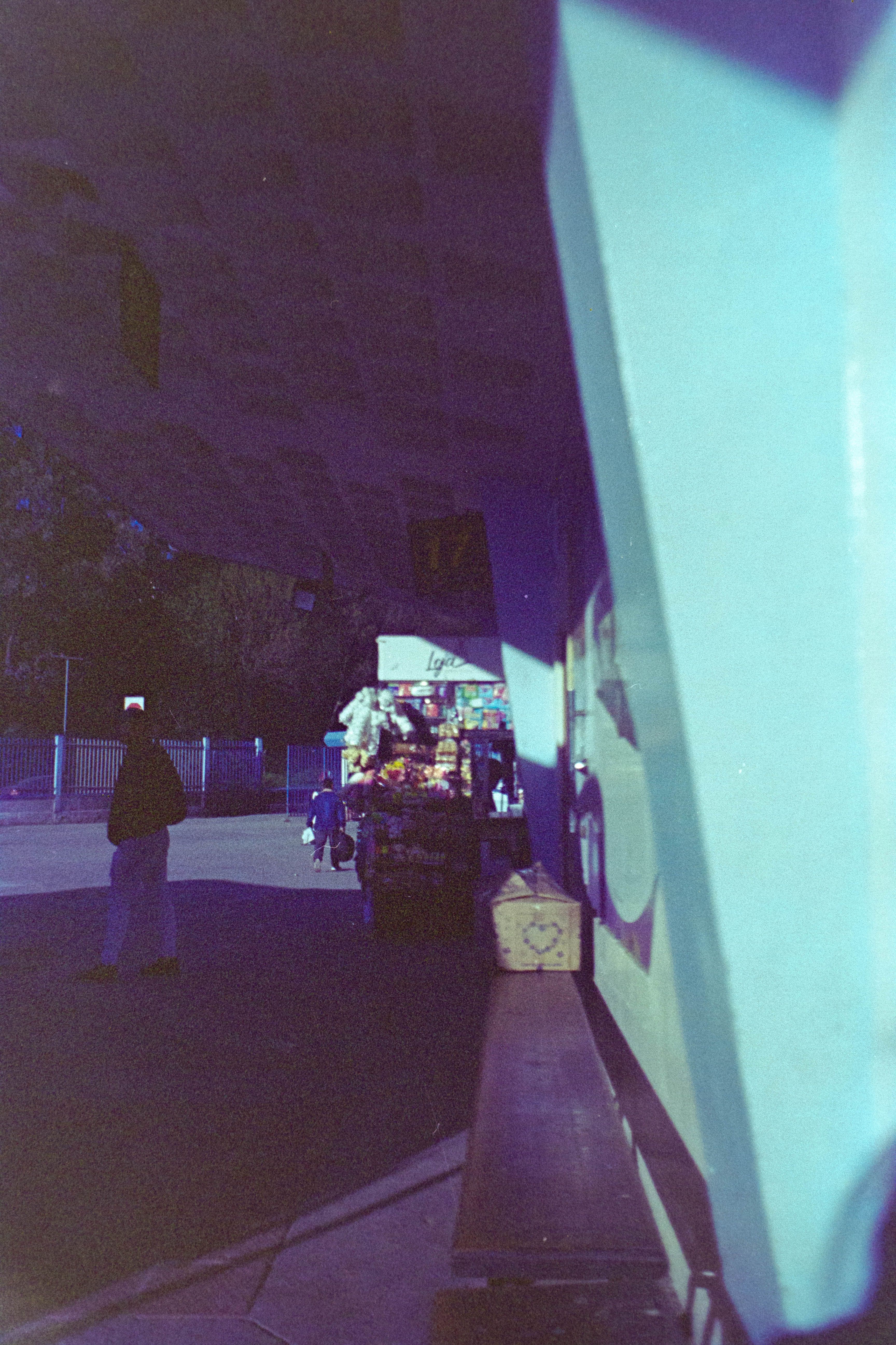 Grainy Film Photo of a Bus Stop and a Food Stall in City · Free Stock Photo