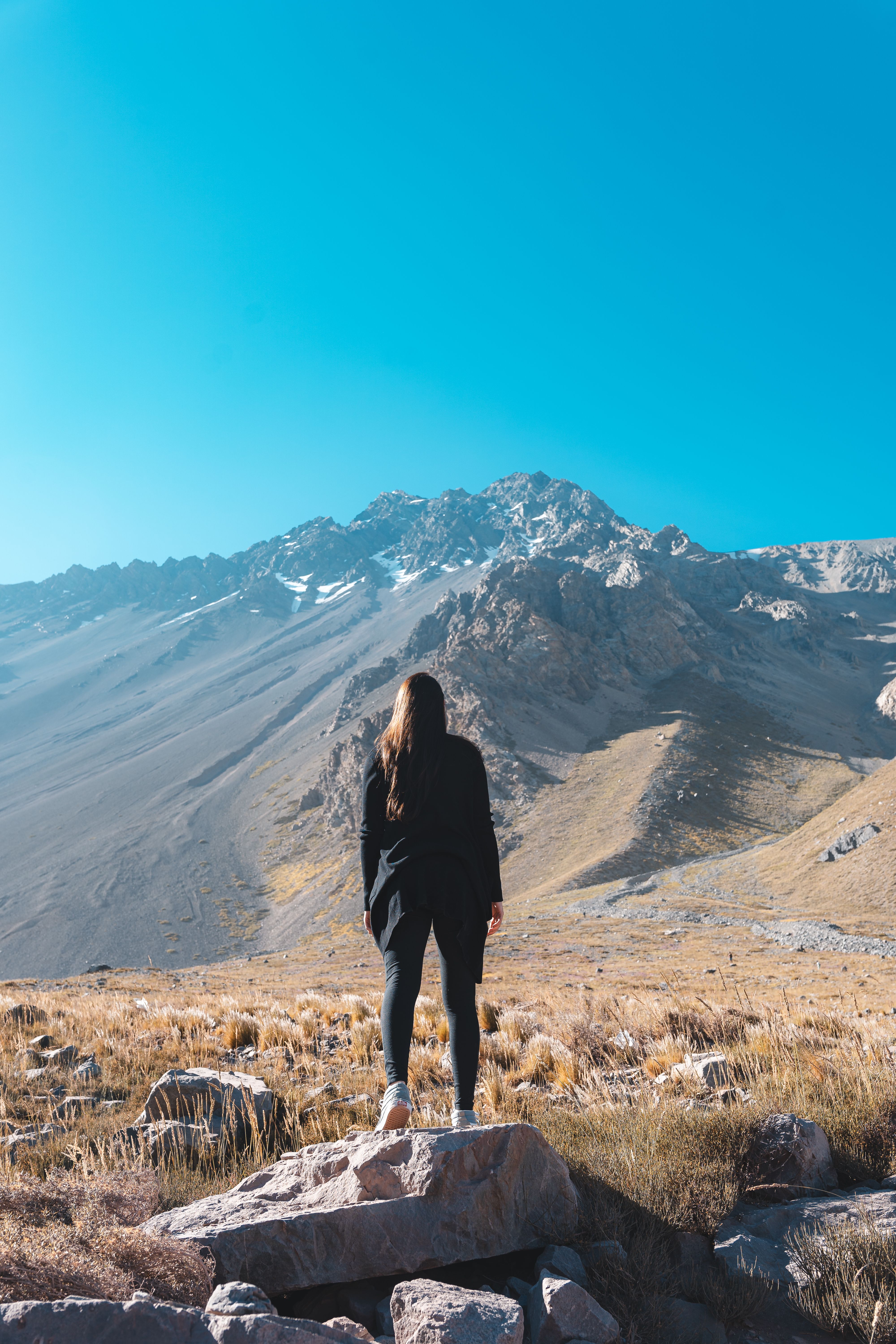 Woman Standing on Rock with Mountains behind · Free Stock Photo