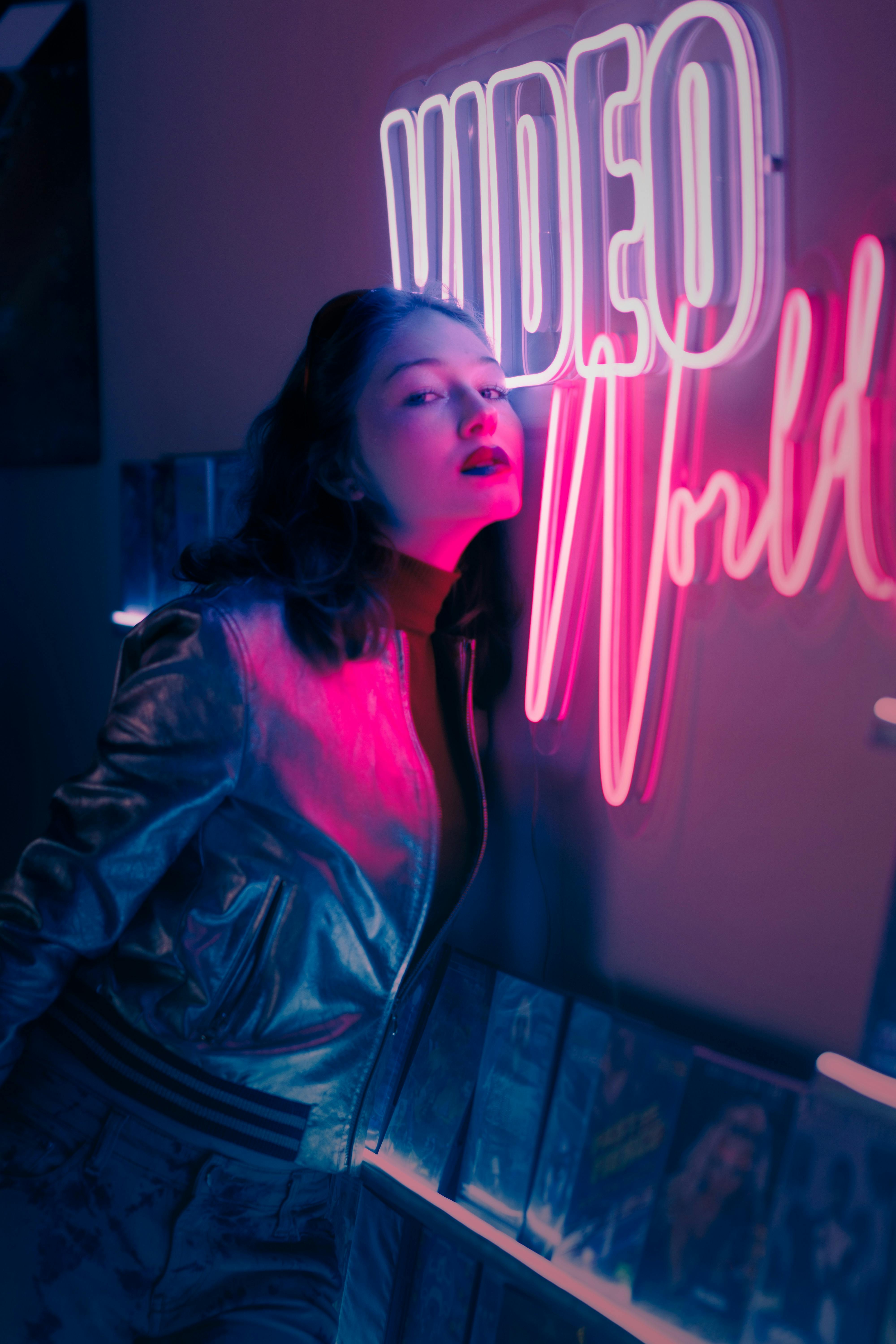 Woman Standing by Neon on Wall · Free Stock Photo
