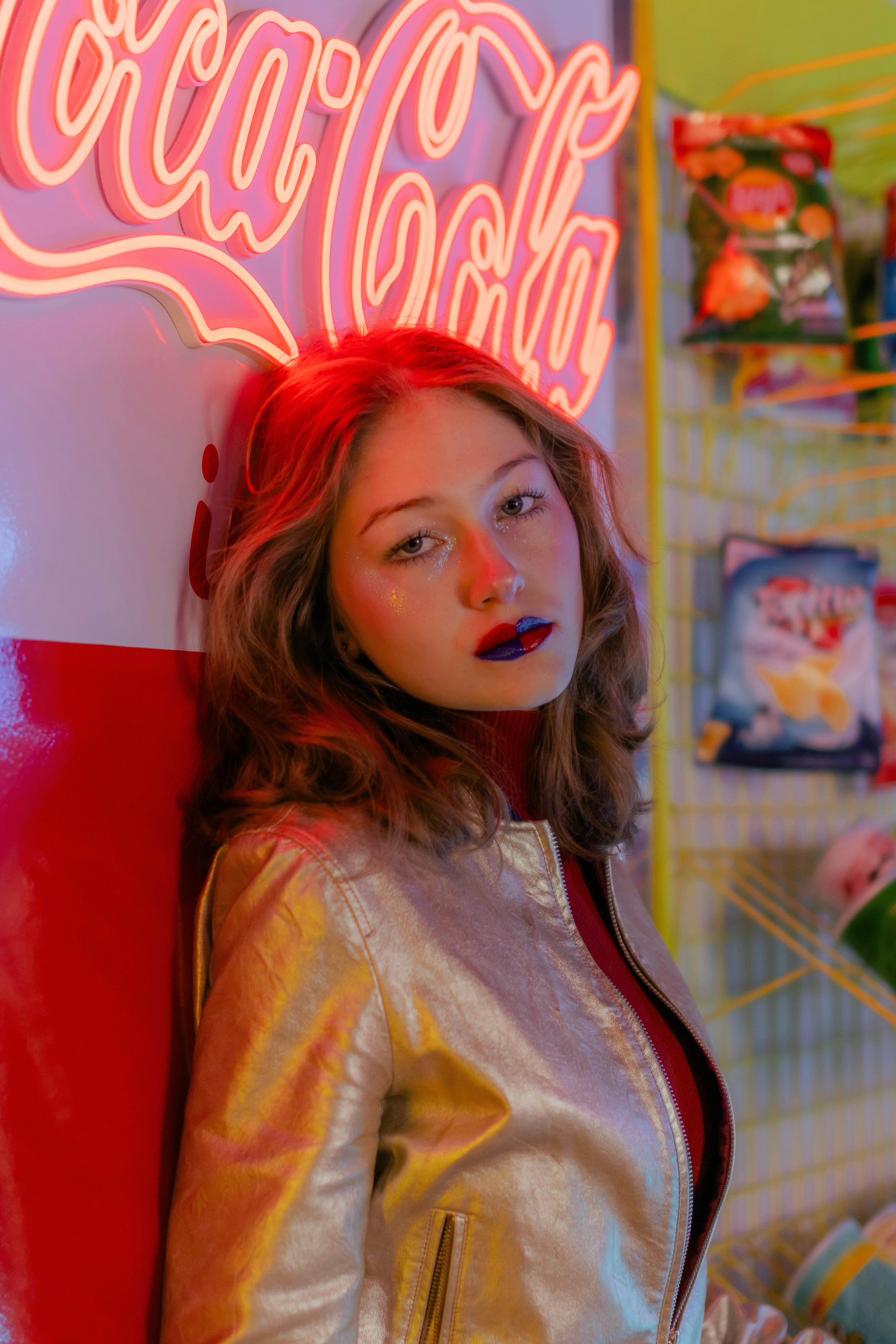Woman Leaning under Coca Cola Neon on Wall · Free Stock Photo