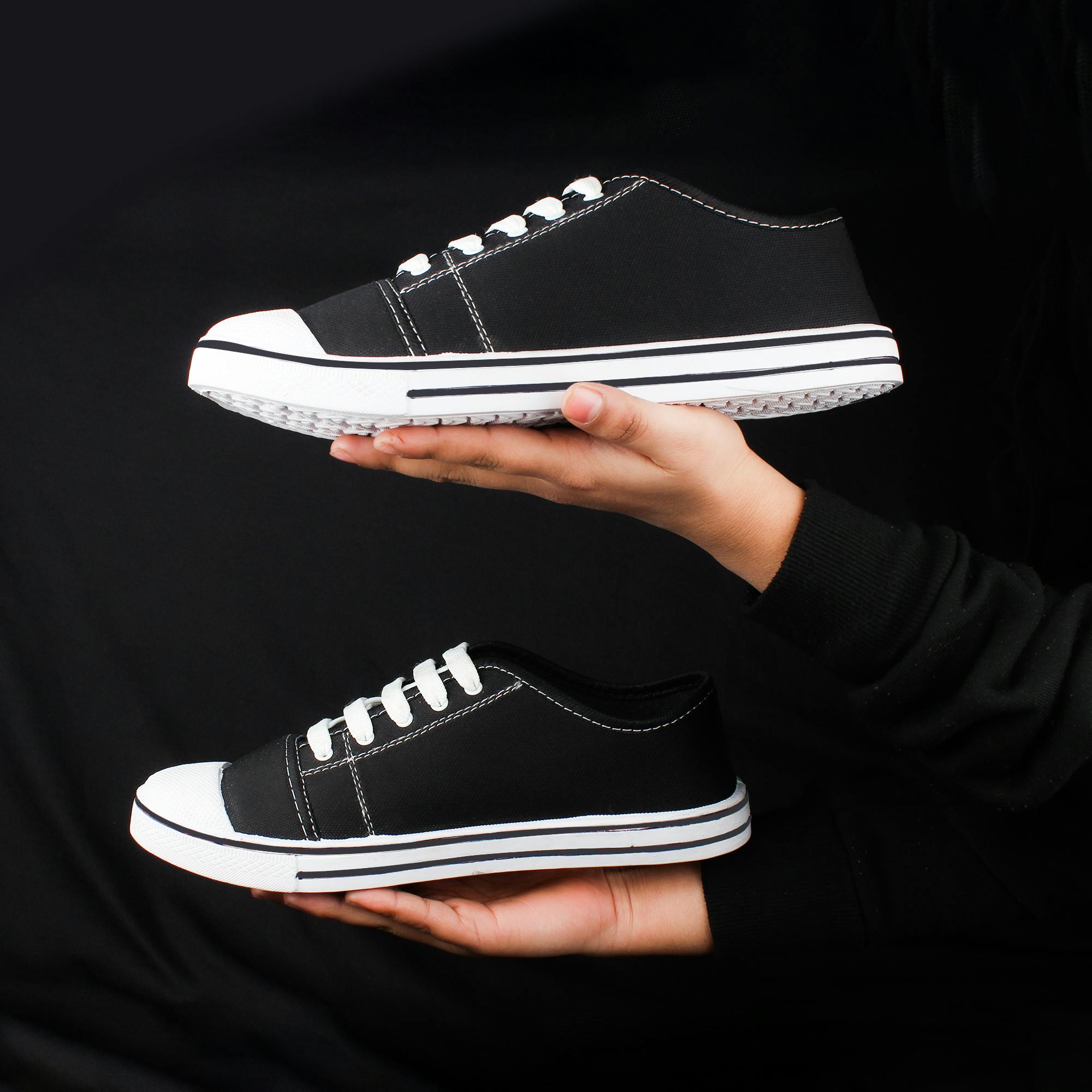 Hands Holding a Pair of Black Sneakers · Free Stock Photo