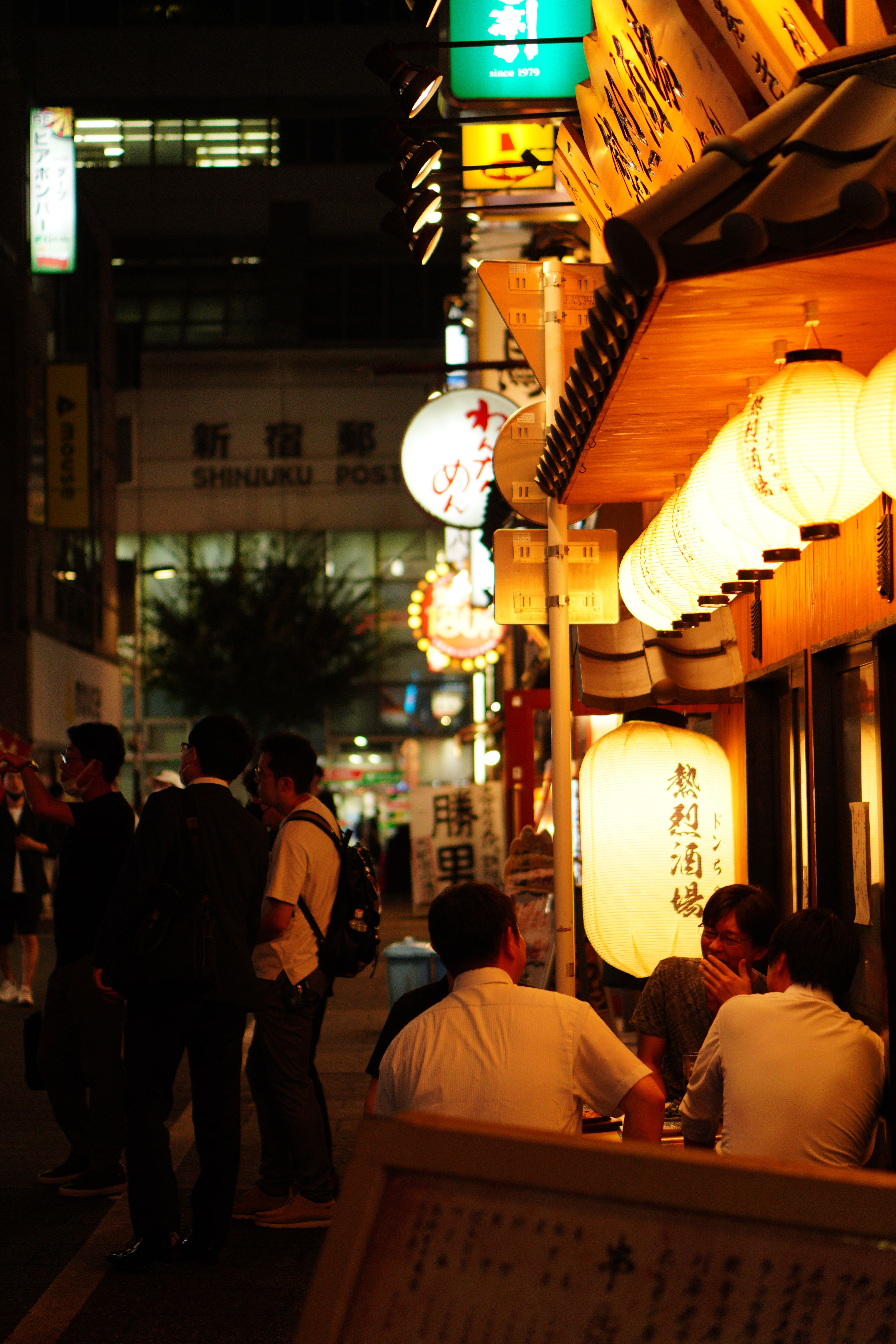 People Sitting outside a Bar Illuminated with Paper Lanterns at Night ...