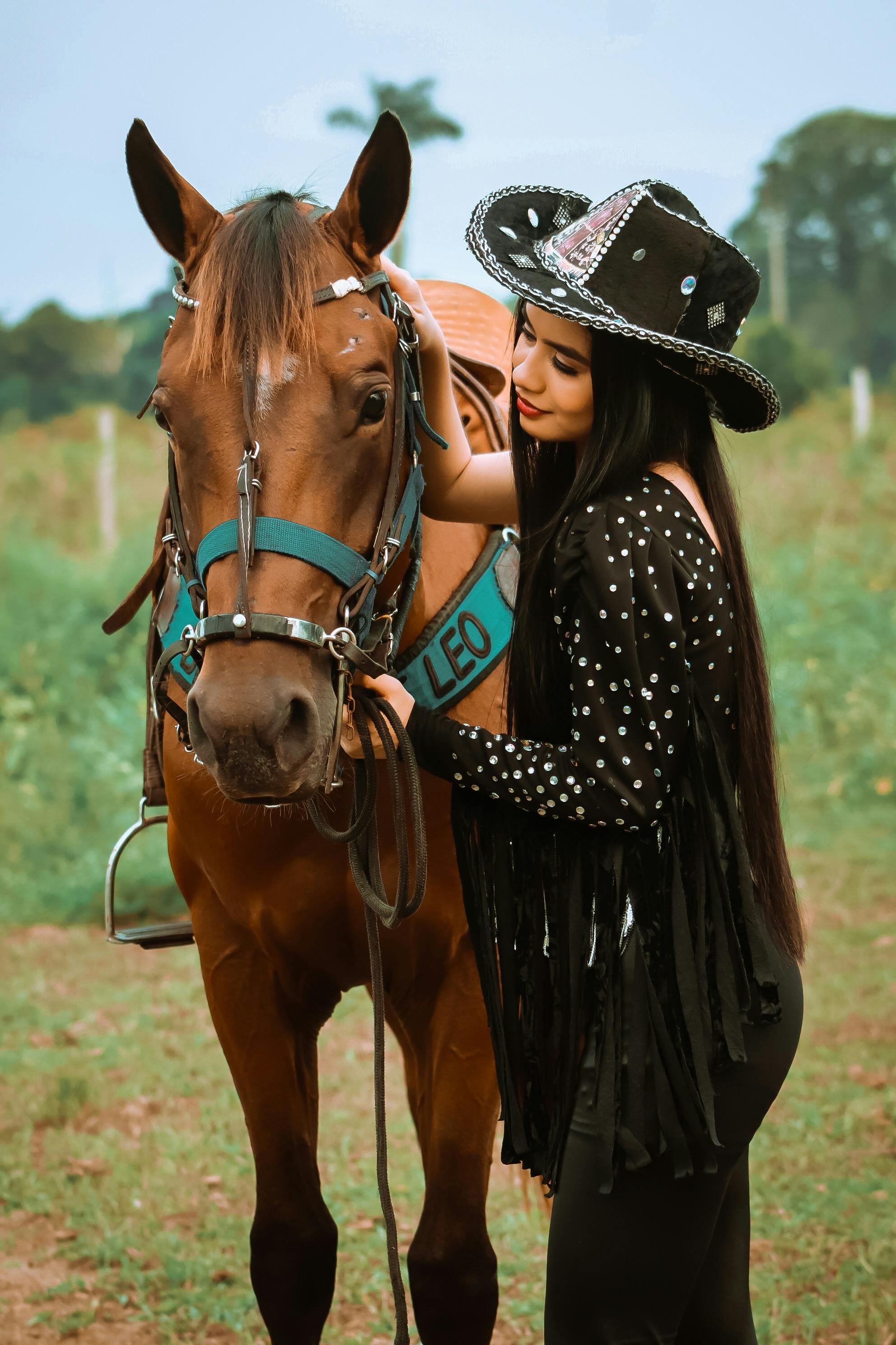 Young Woman in a Cowboy Hat and a Fringe Blouse by a Chestnut Horse · Free Stock Photo