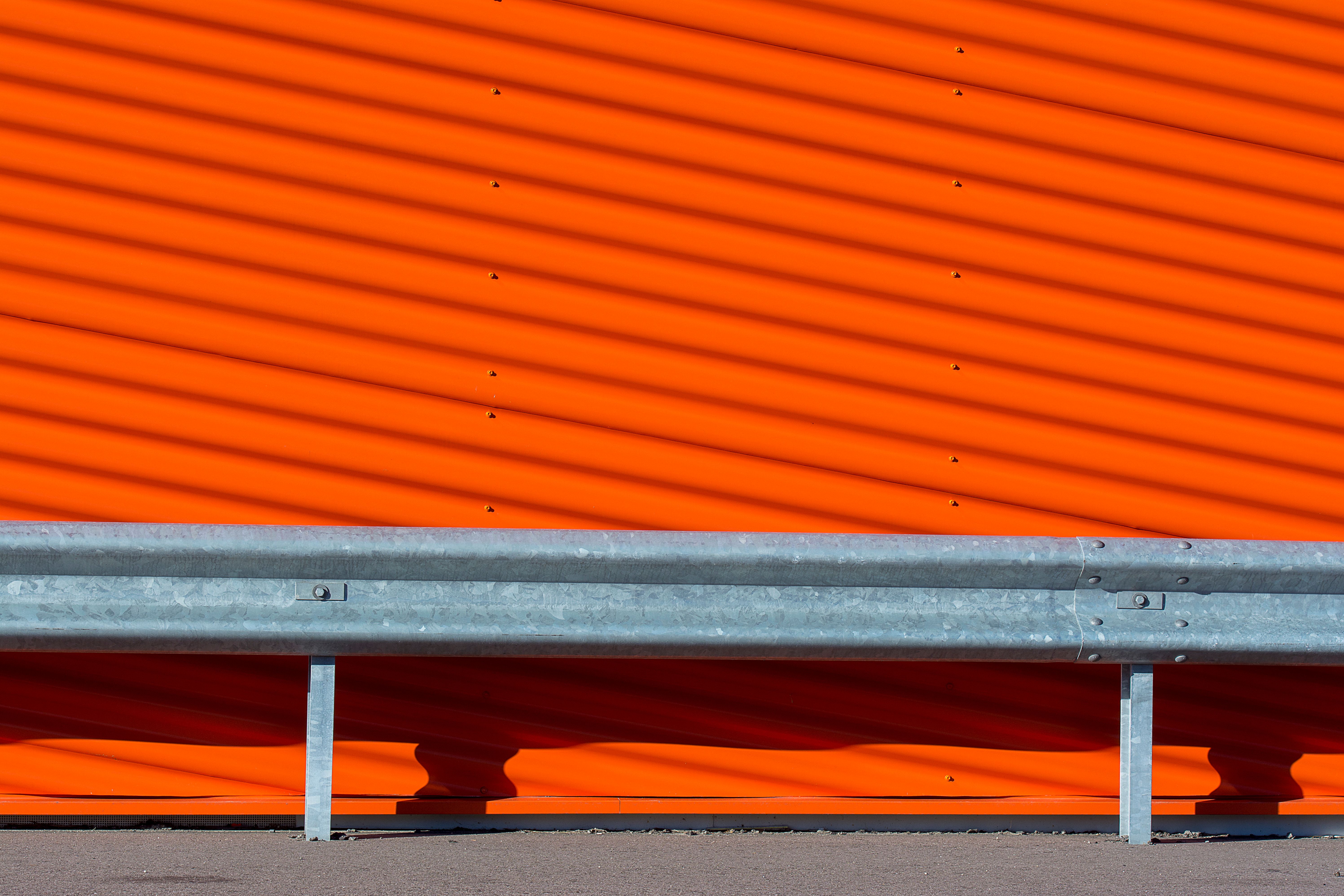 Close-up of a Road Barrier against a Bright Orange Wall · Free Stock Photo