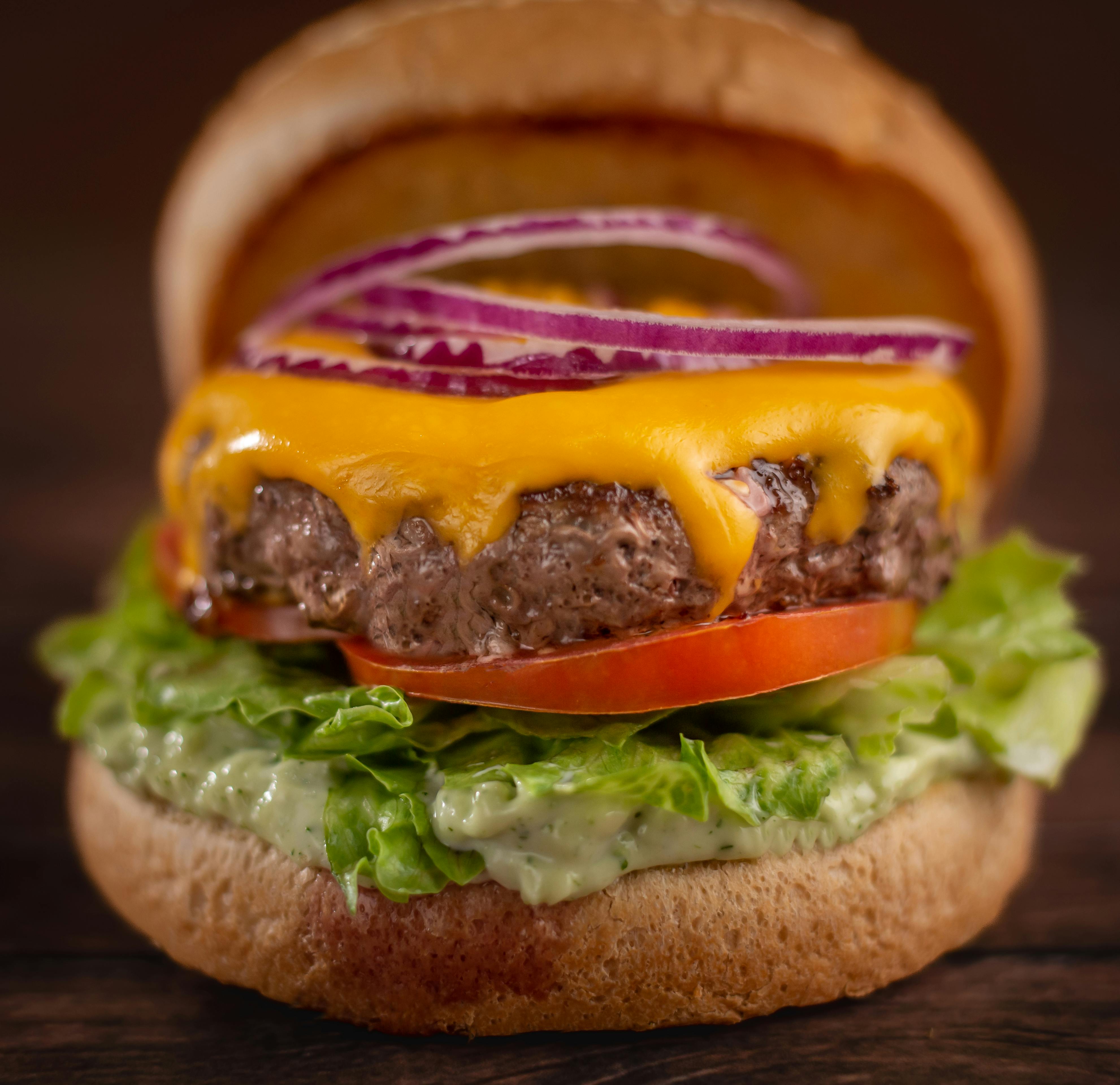 A cheeseburger with lettuce, tomato and onion · Free Stock Photo