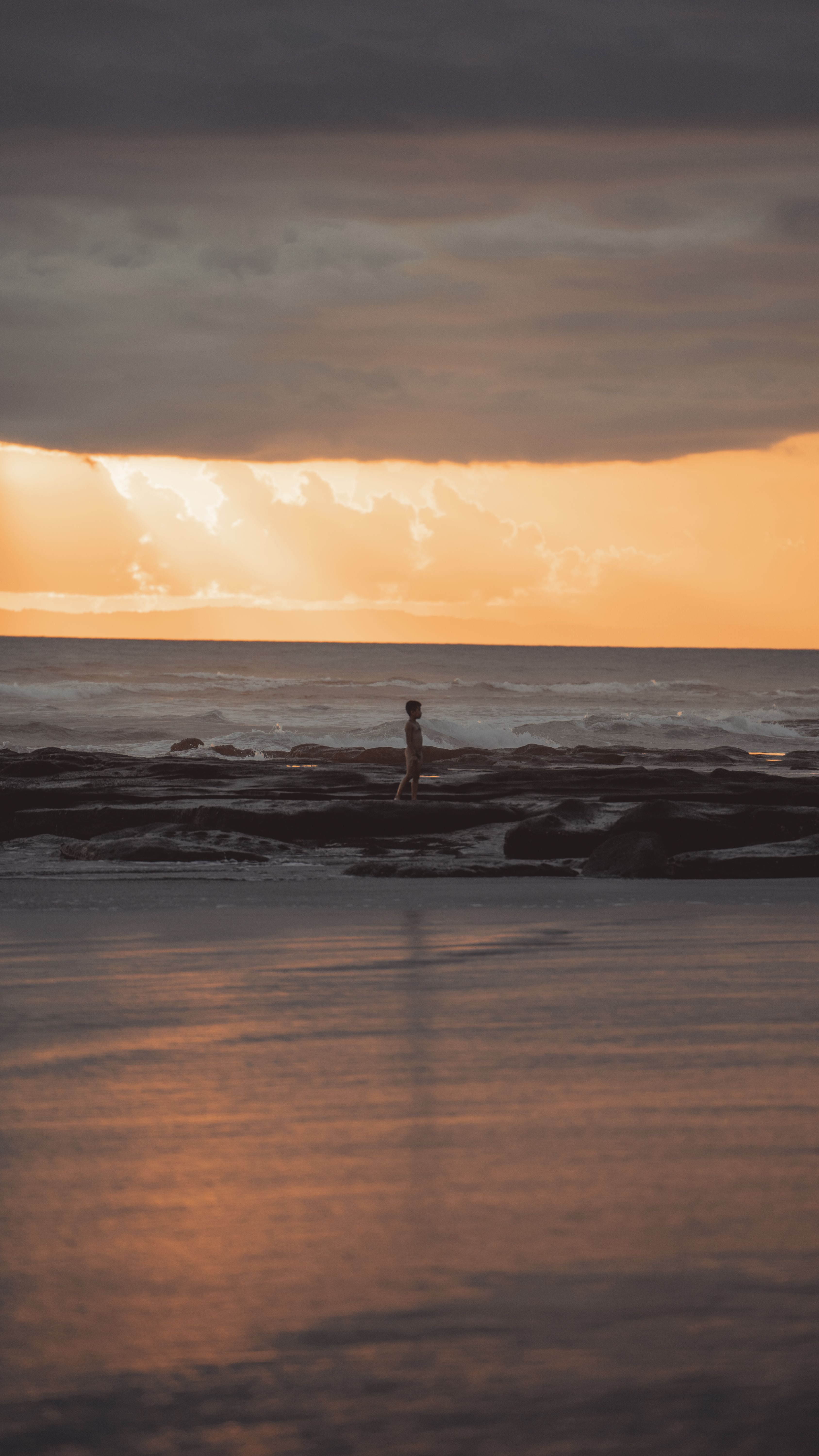 Person Standing on Rocks on Sea Shore at Sunset · Free Stock Photo