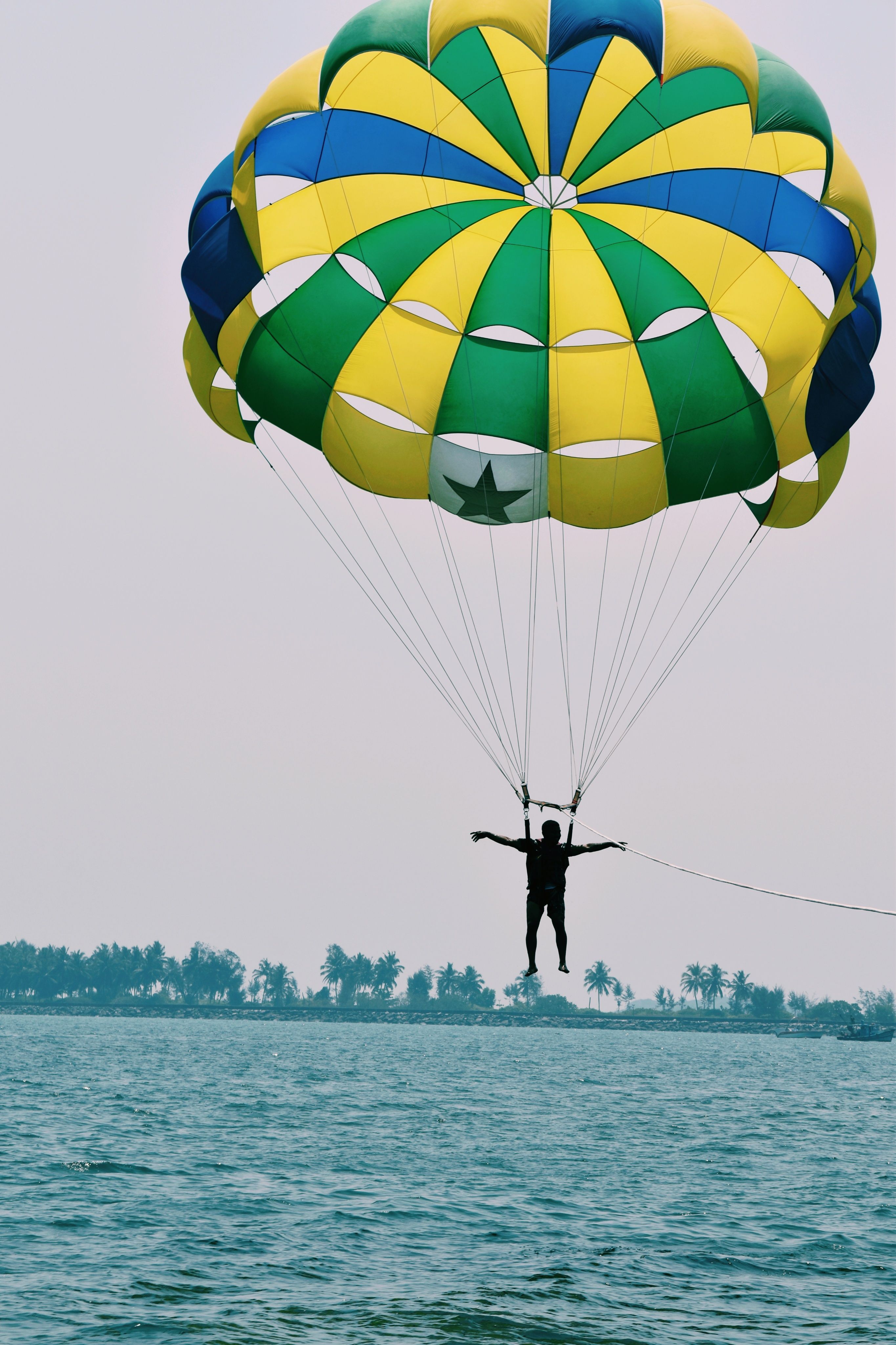 A Person with a Parachute Flying over a Body of Water · Free Stock Photo