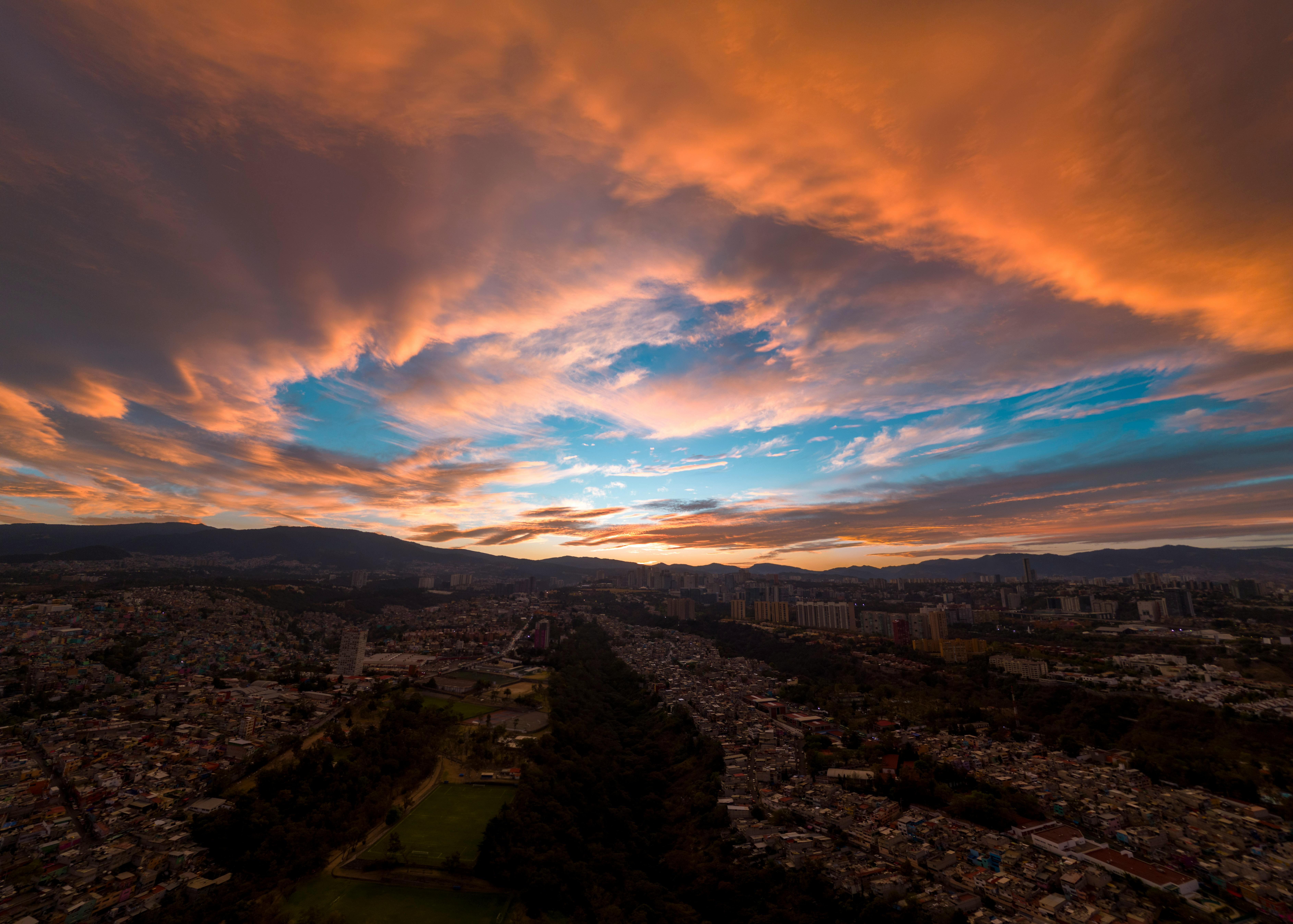A colorful sunset over a city and hills · Free Stock Photo