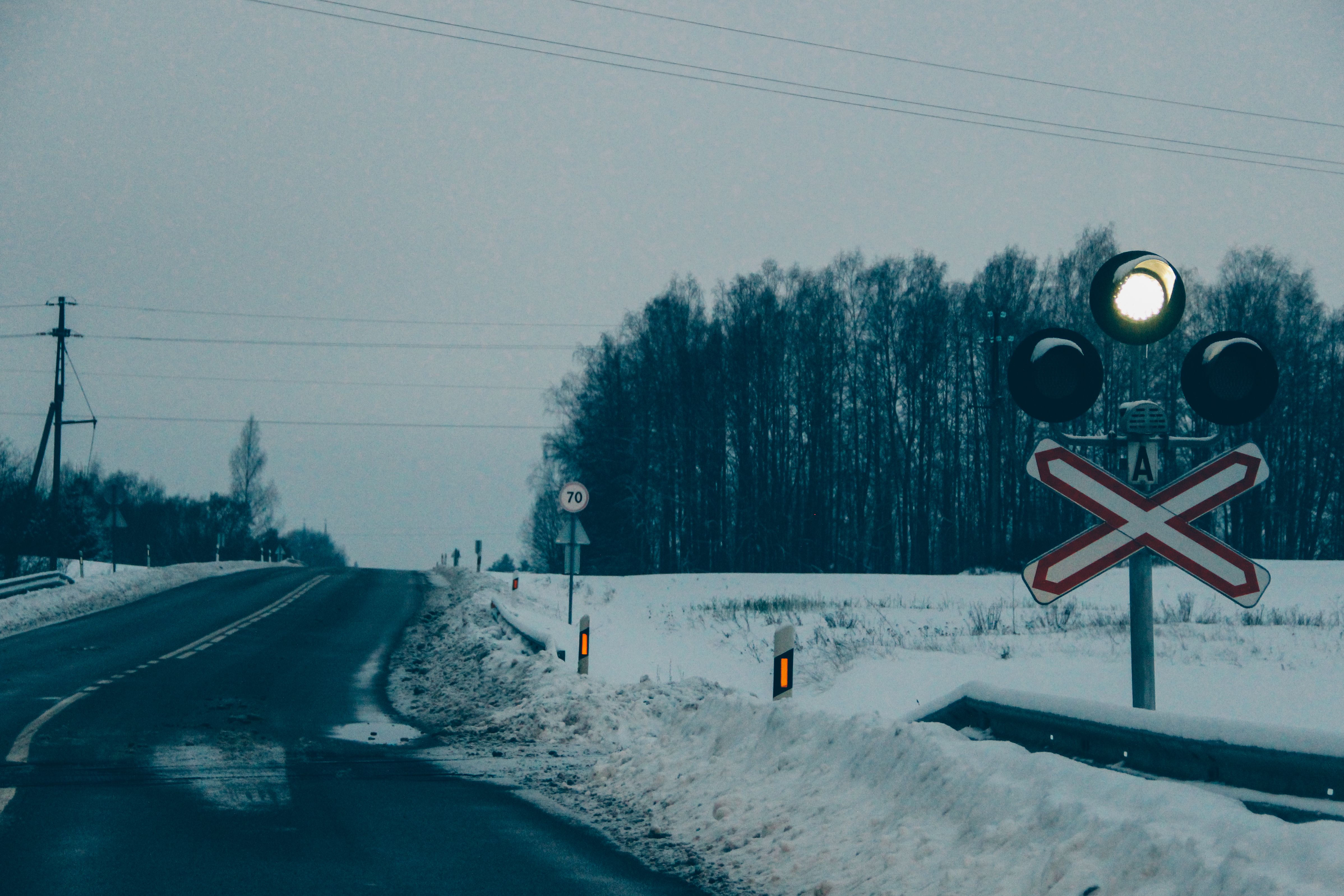 A road with a train crossing sign in the snow · Free Stock Photo