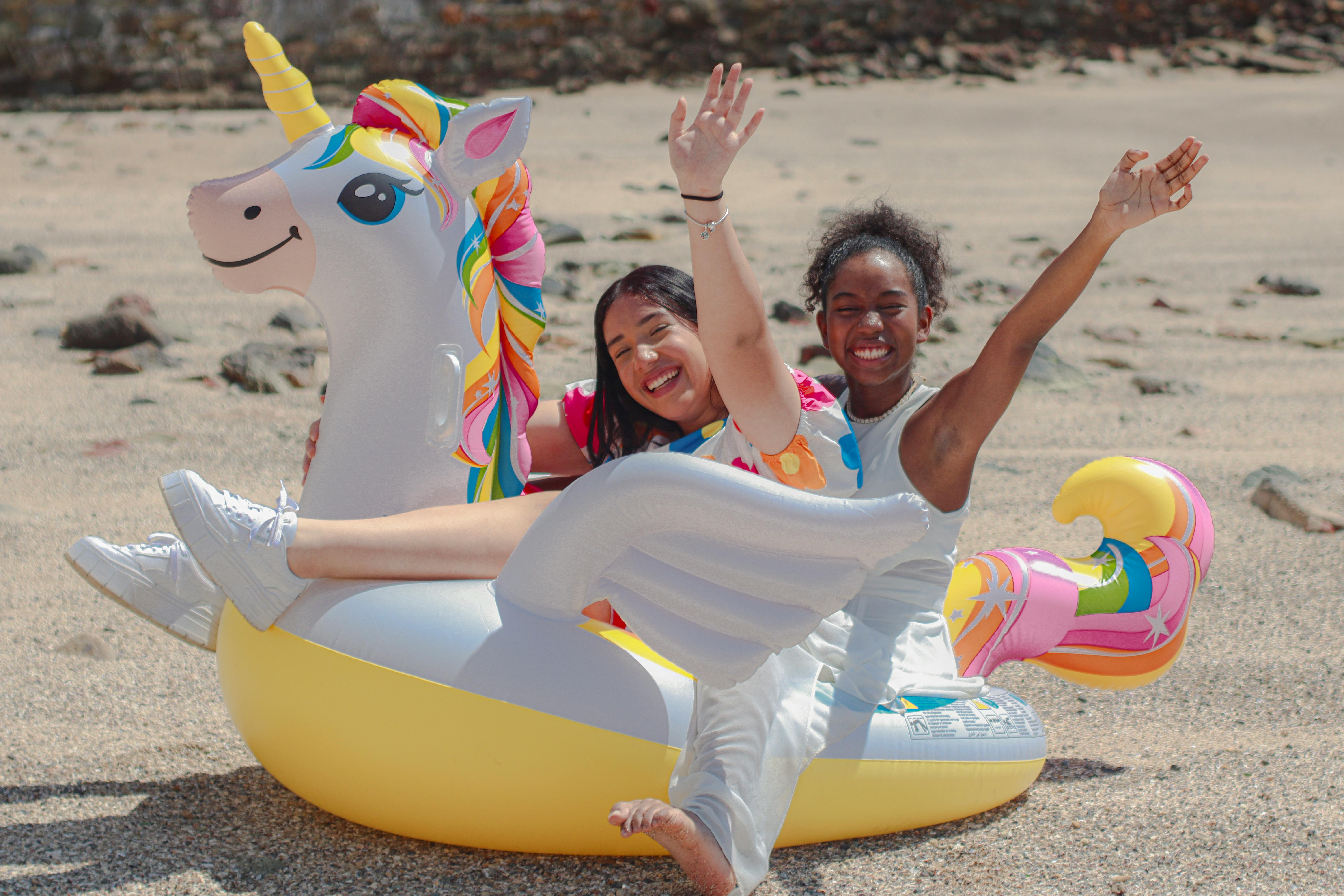 Smiling Women Sitting on Inflatable Unicorn · Free Stock Photo