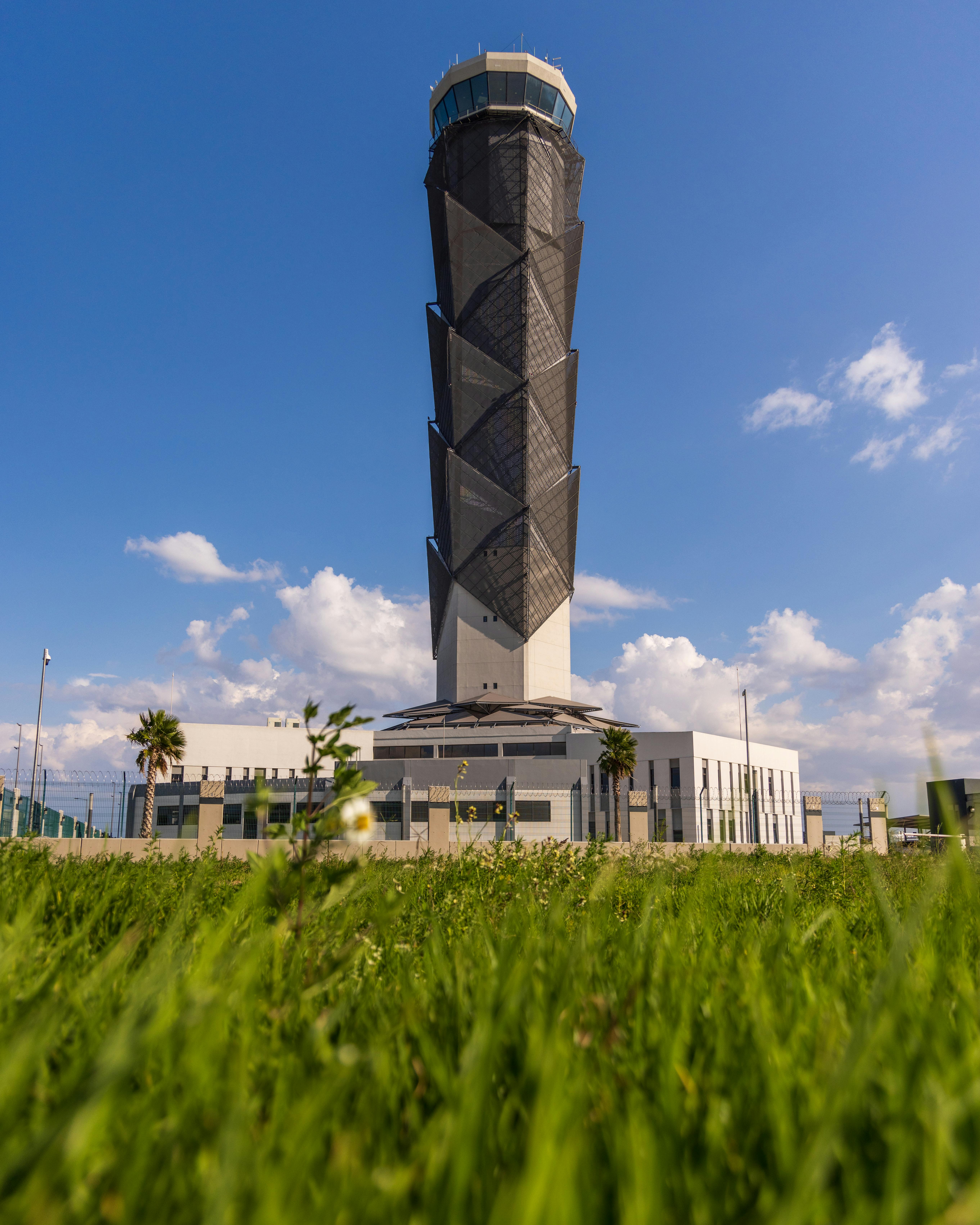 A tall tower with a green grassy field in the background · Free Stock Photo