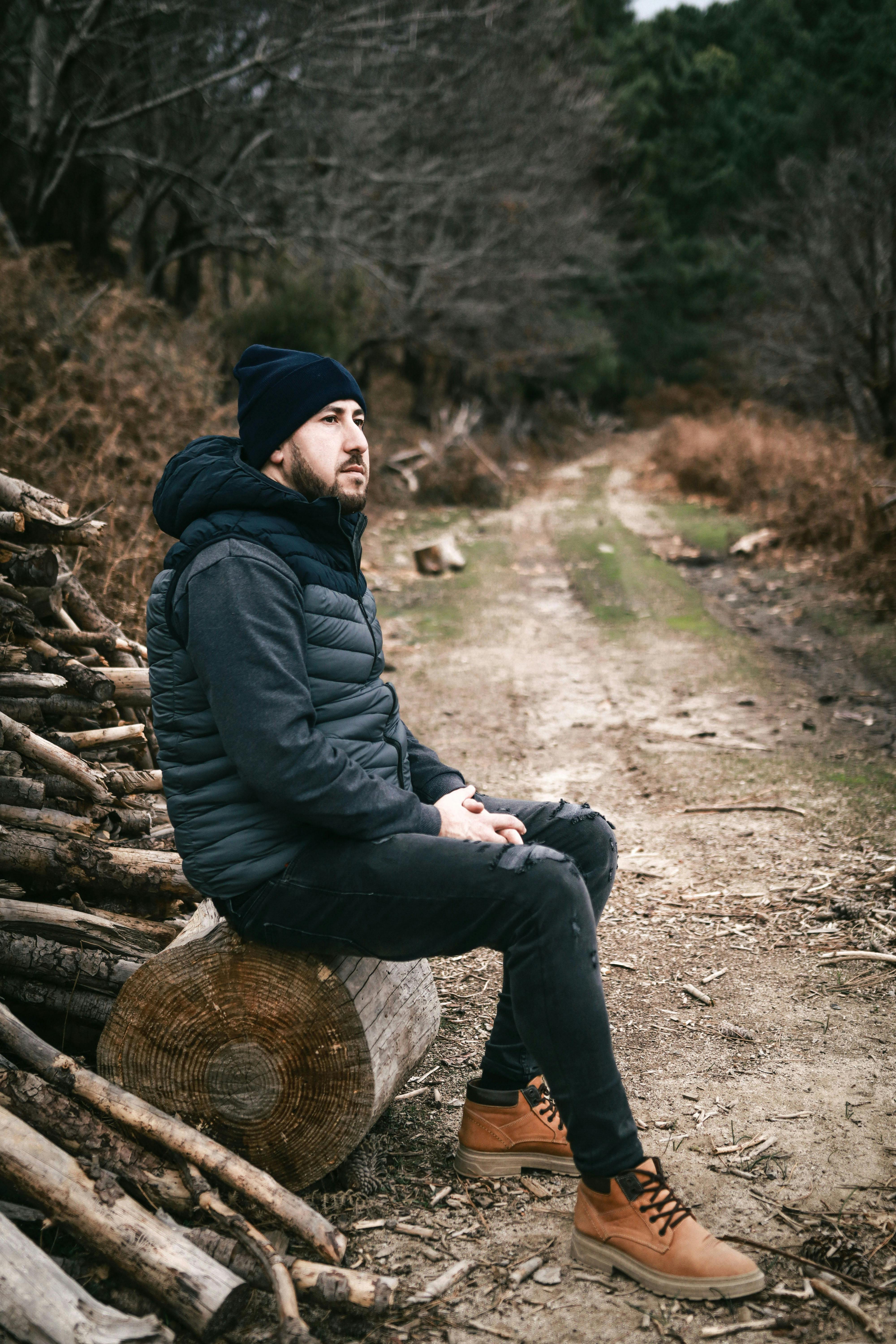 Man in Black Jacket Sitting on Tree Log in Forest · Free Stock Photo