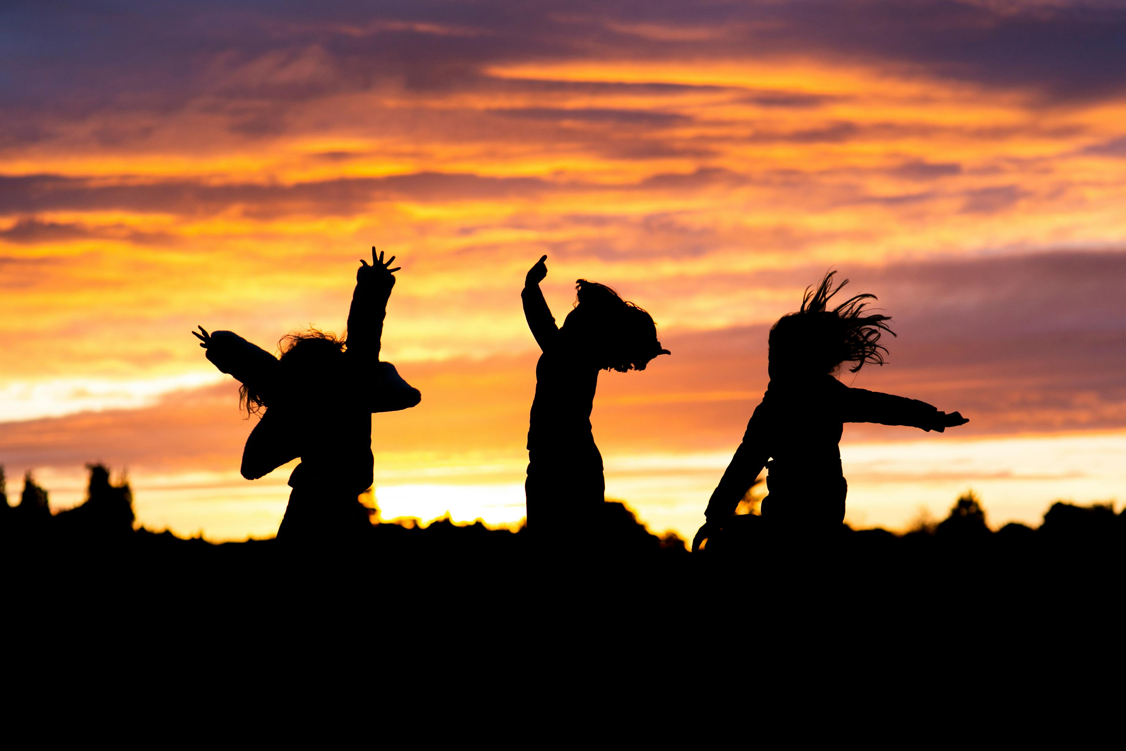 Silhouette of Children Dancing and Jumping at Sunset · Free Stock Photo