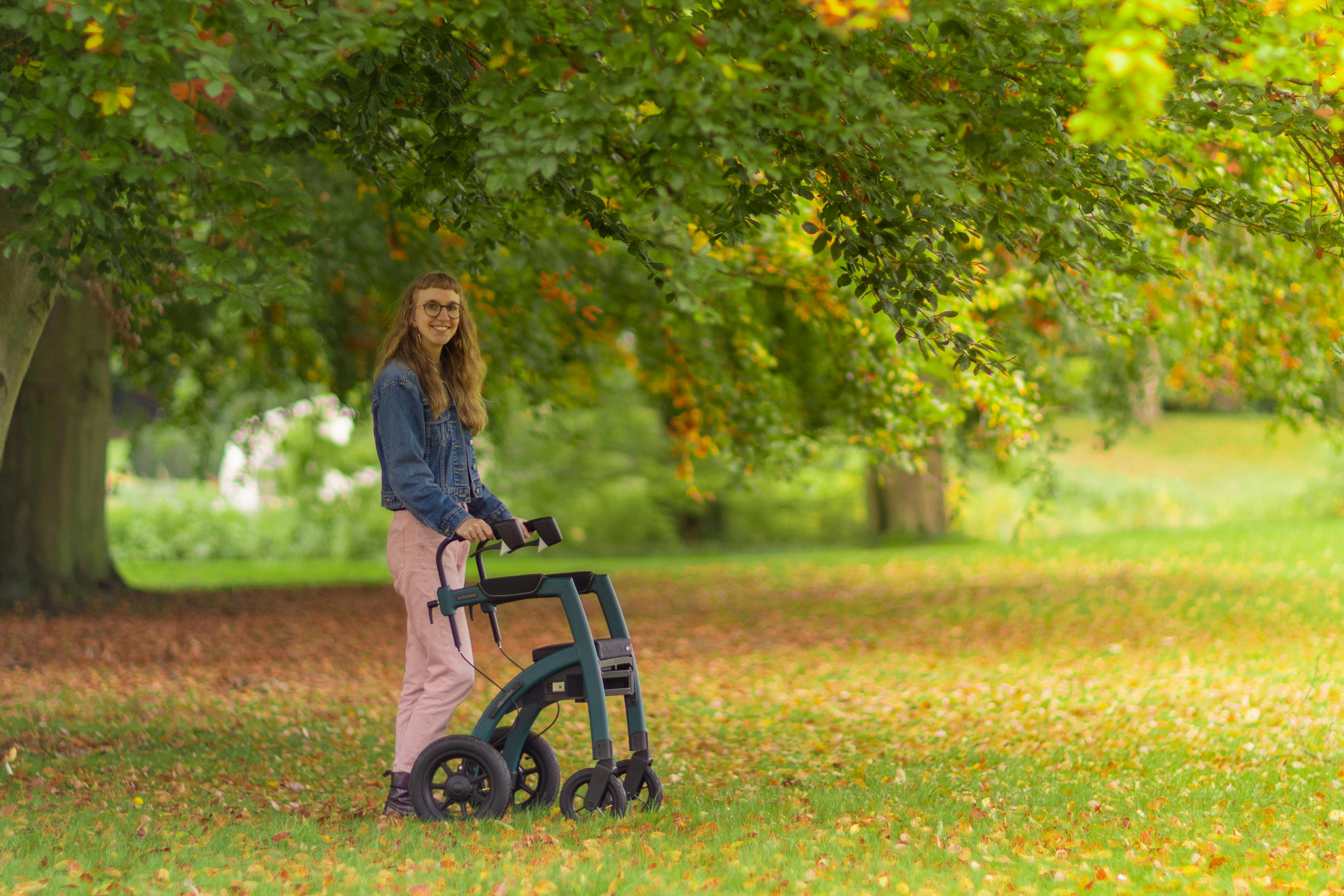 Smiling Woman with Walker under Green Trees · Free Stock Photo