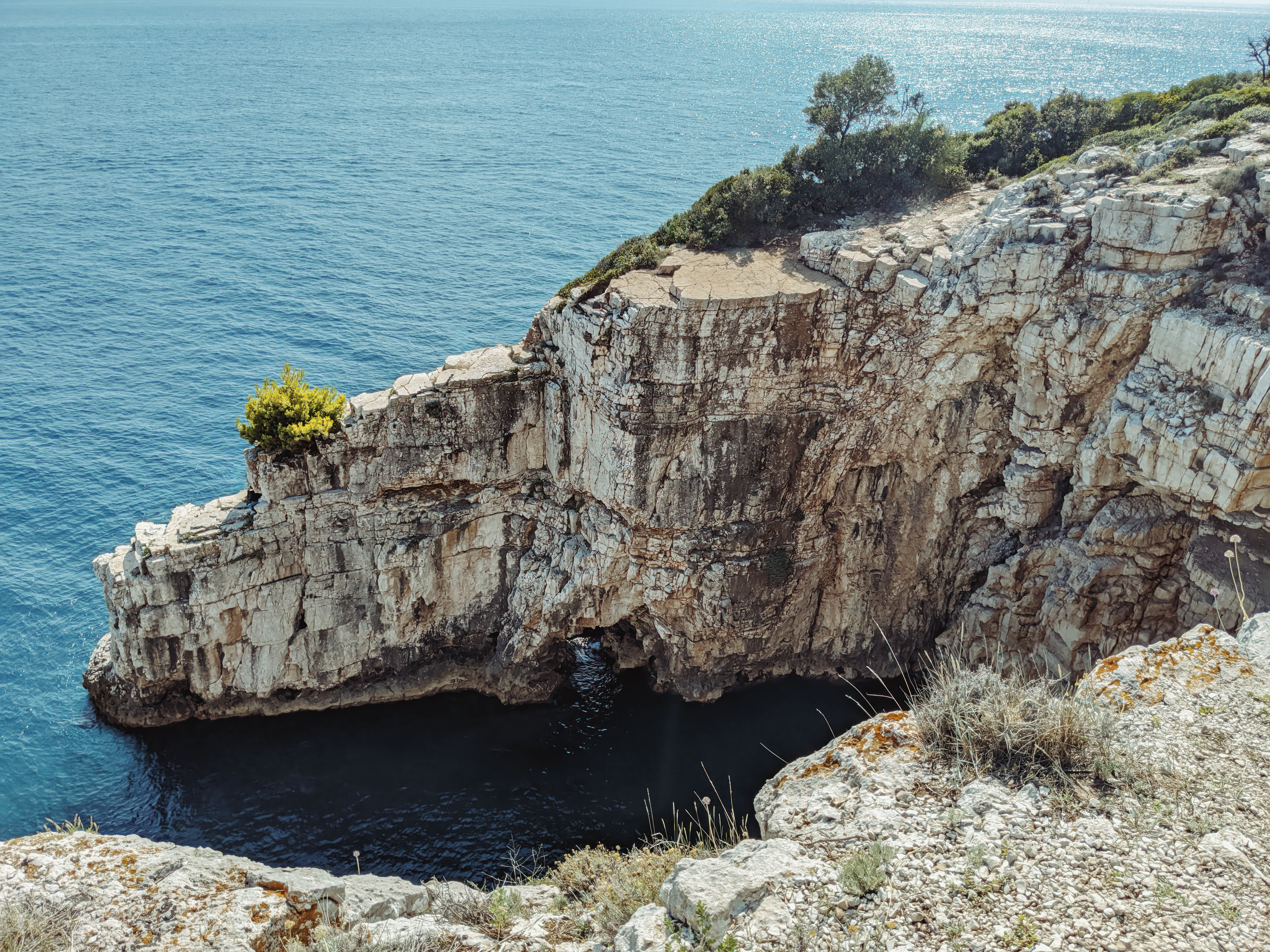 A cliff with a small rock in the ocean · Free Stock Photo