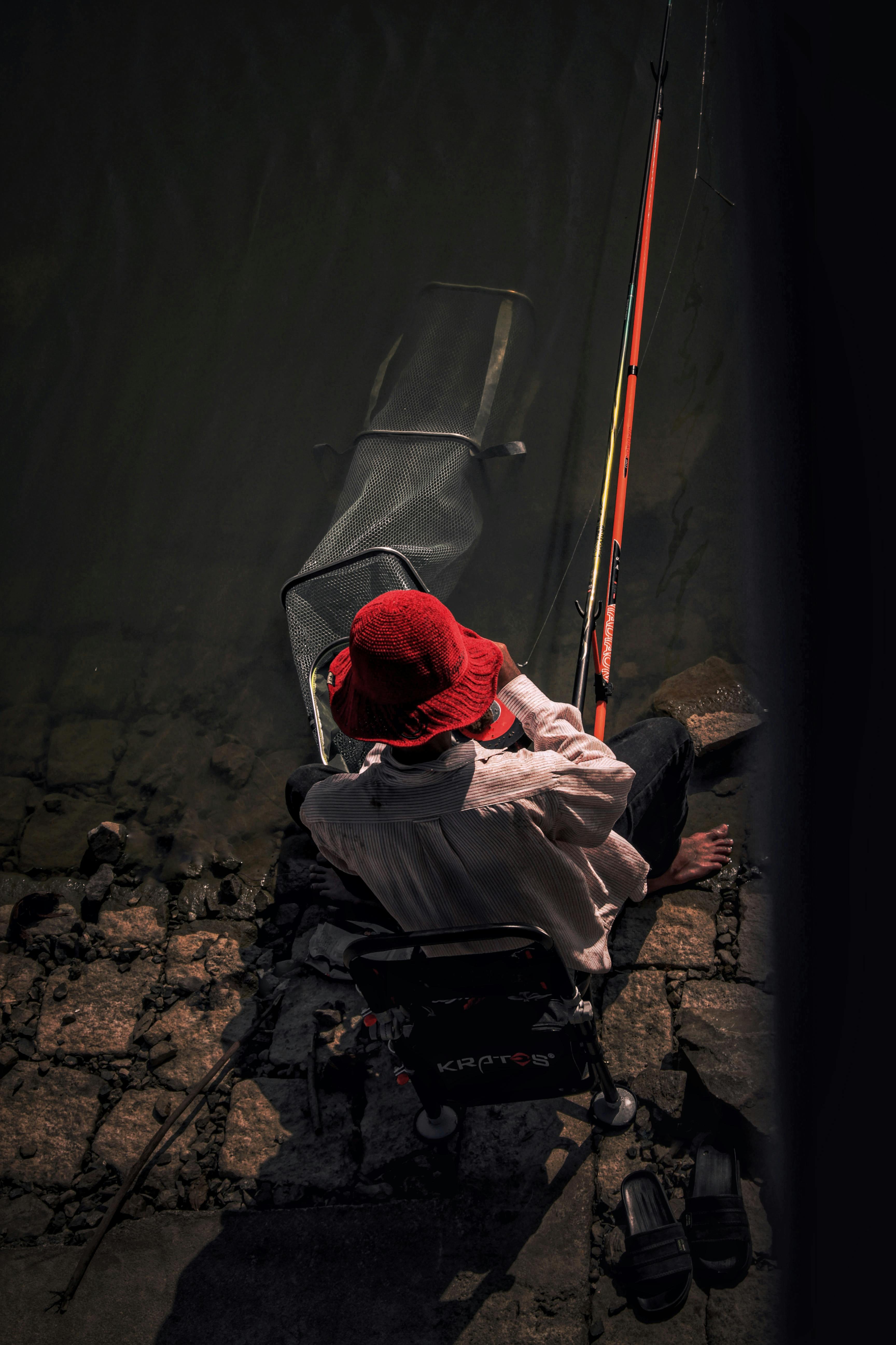 Angler with Fishing Rod and Net on the Cobblestone Shore · Free Stock Photo