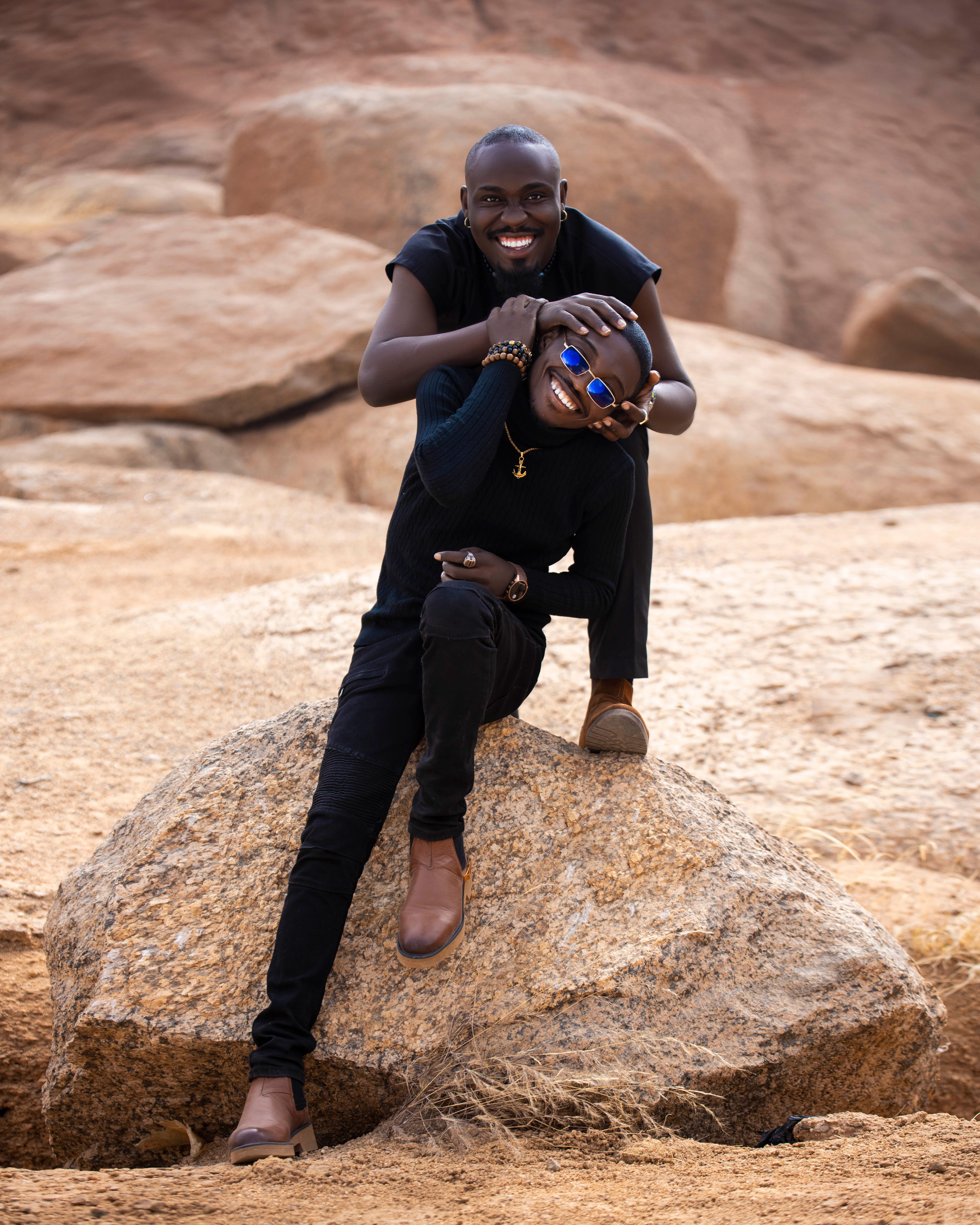Smiling Men Posing on Rocks · Free Stock Photo