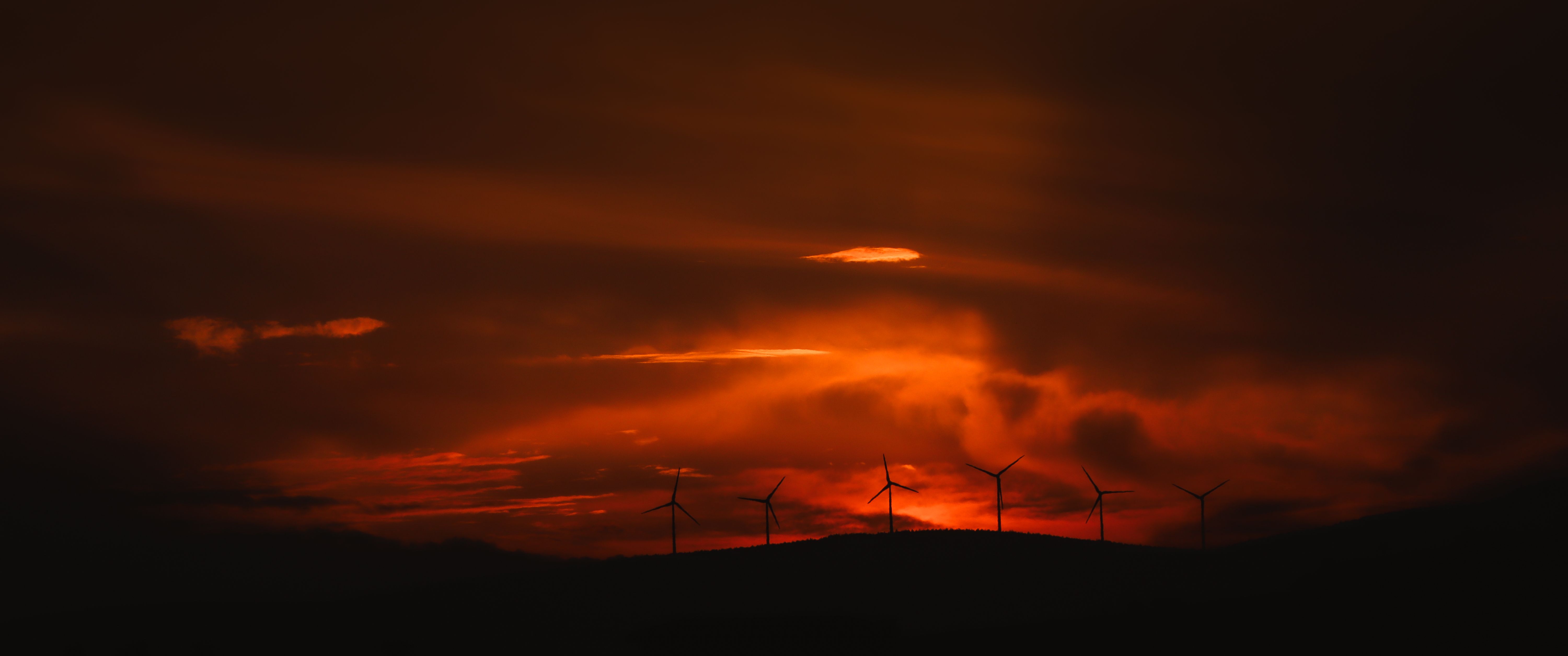 A sunset with a dark sky and some wind turbines · Free Stock Photo