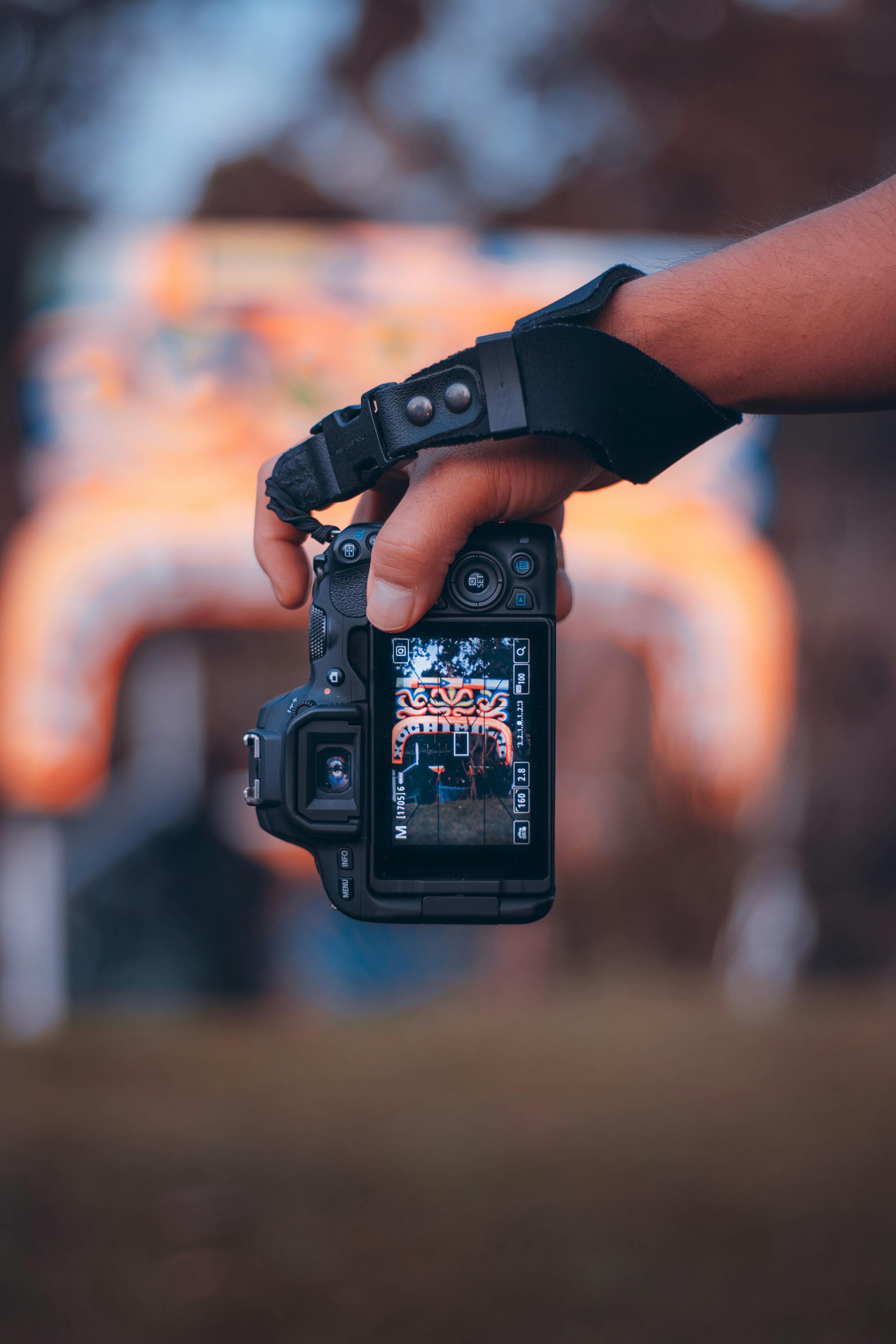 Photo of Hand Holding up a Black Canon Dslr Camera · Free Stock Photo
